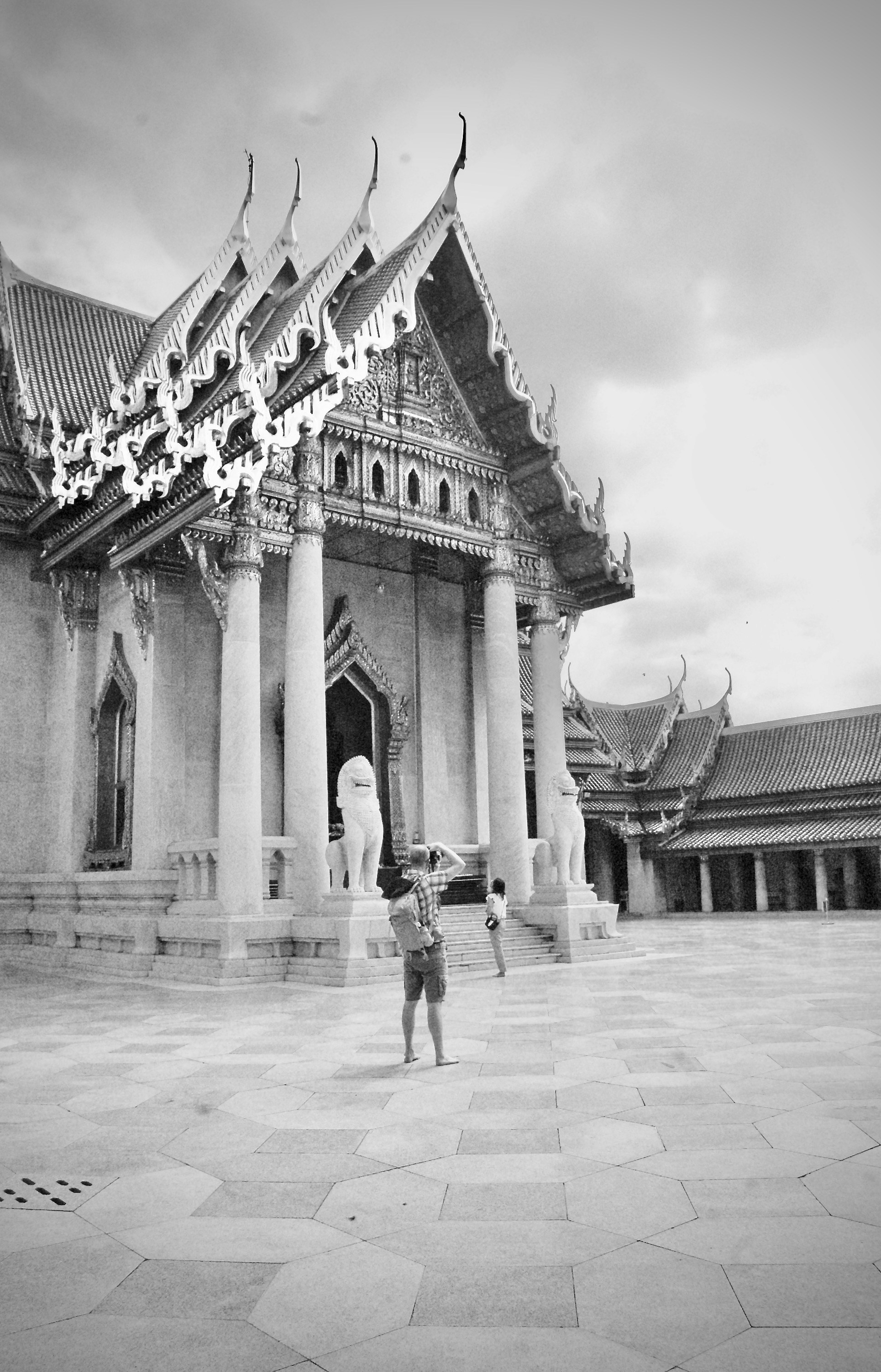 Temple Courtyard in Monochrome: A Tourist Reaches for the Sky
