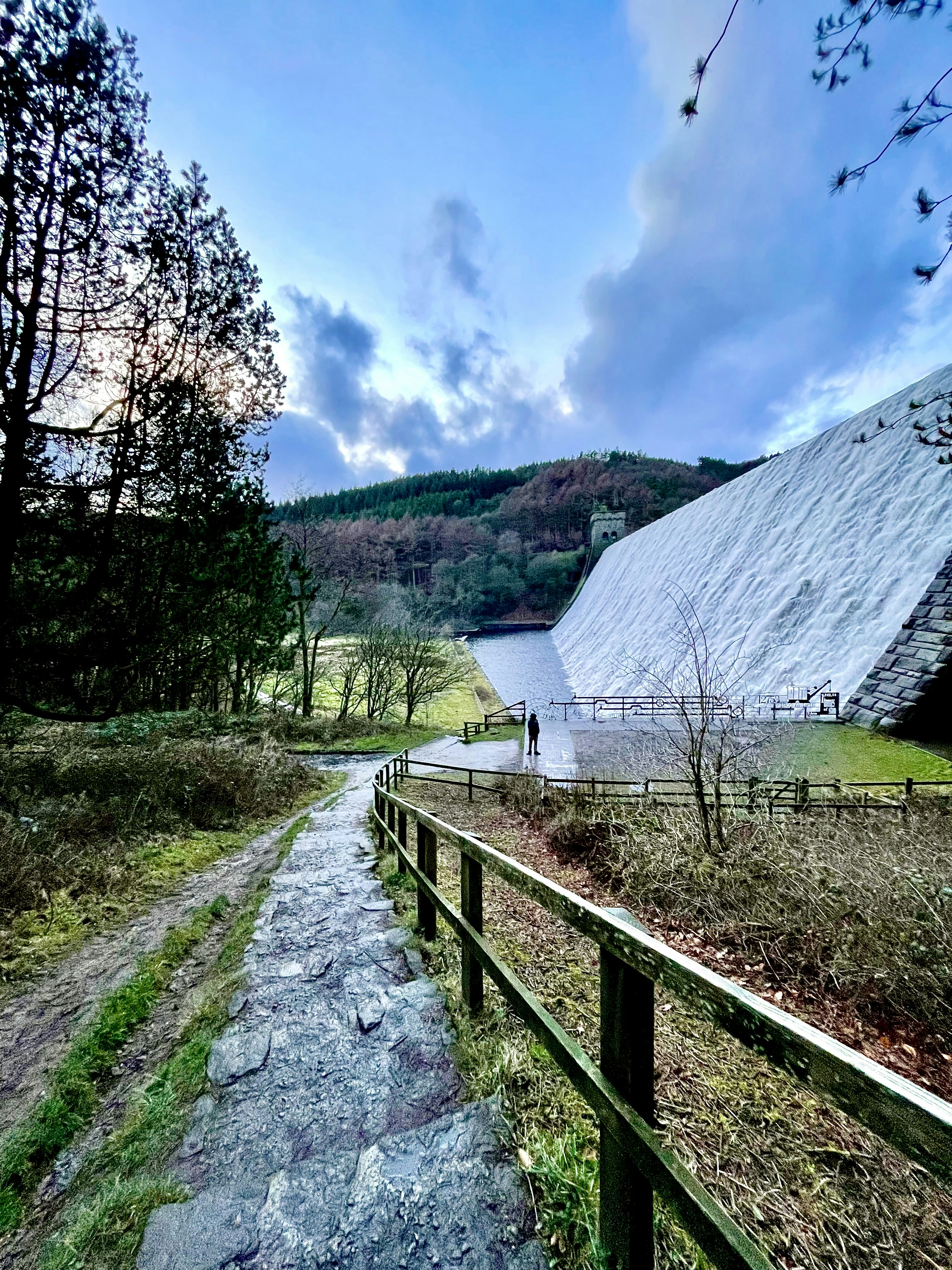 Footpath to the Spillway: A Lone Visitor by the Dam Under a Broad Sky