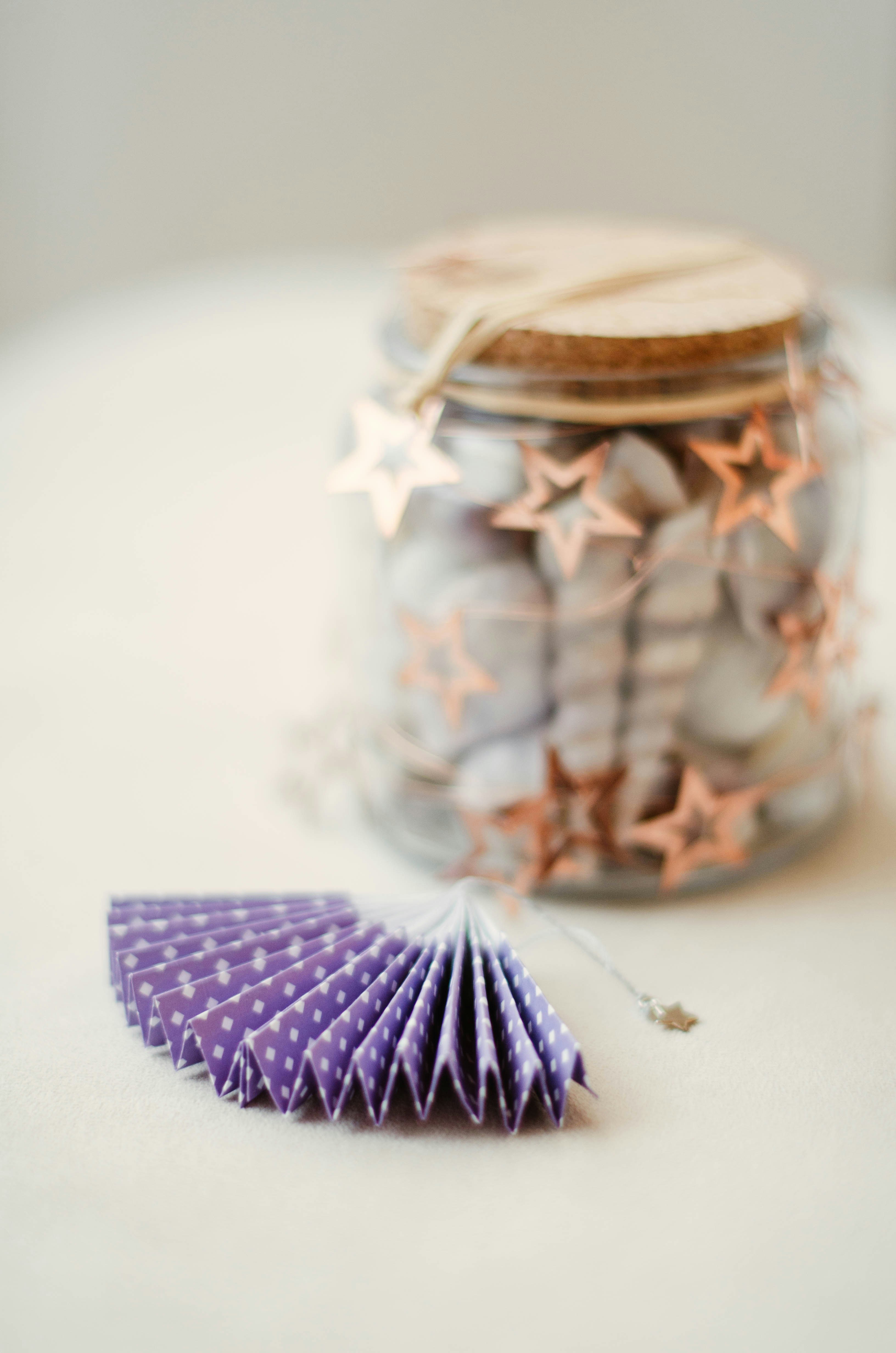 a jar filled with purple paper stars next to a jar of cookies
