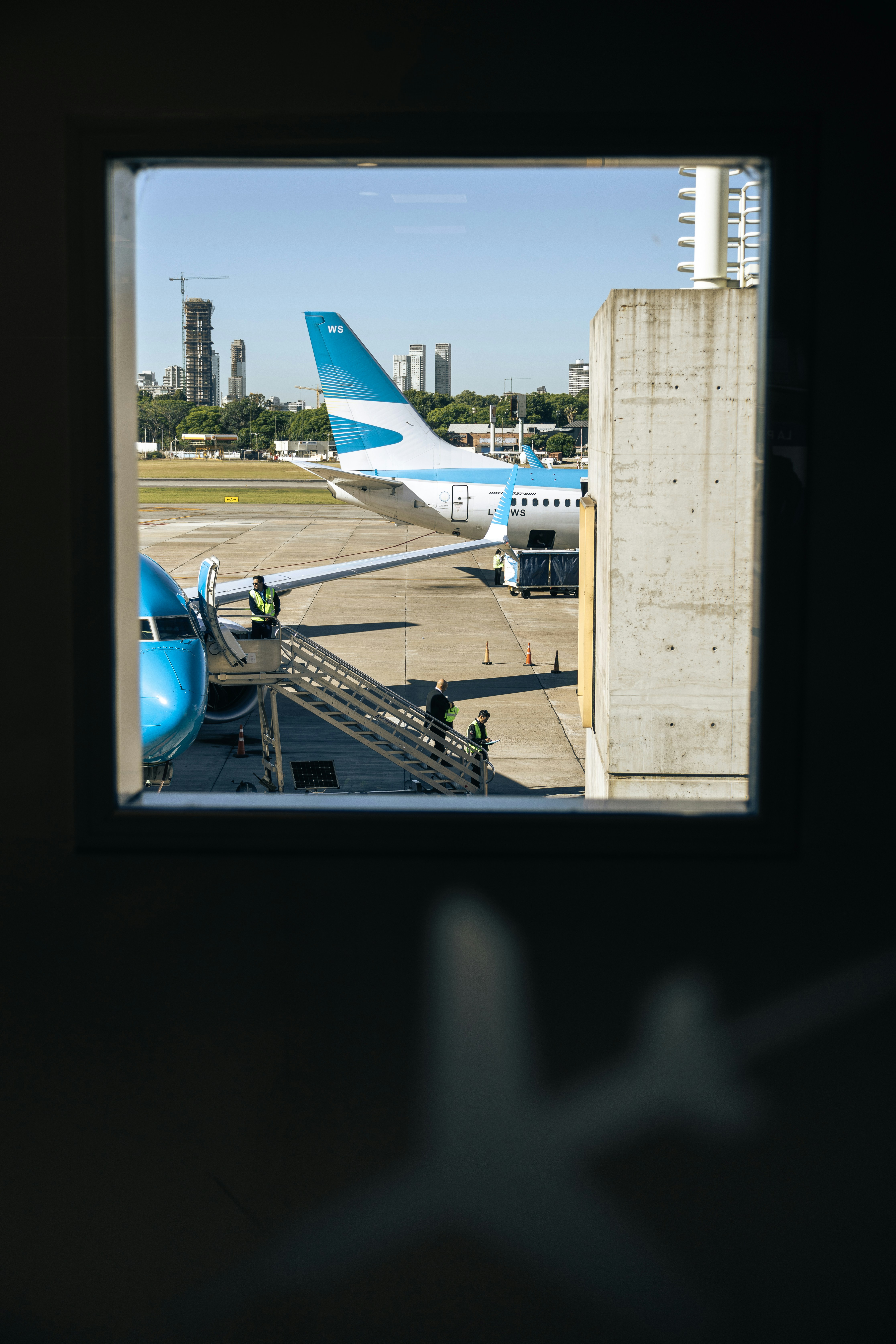 Blue Jet at the Gate: Ground Crew in a Quiet Window View