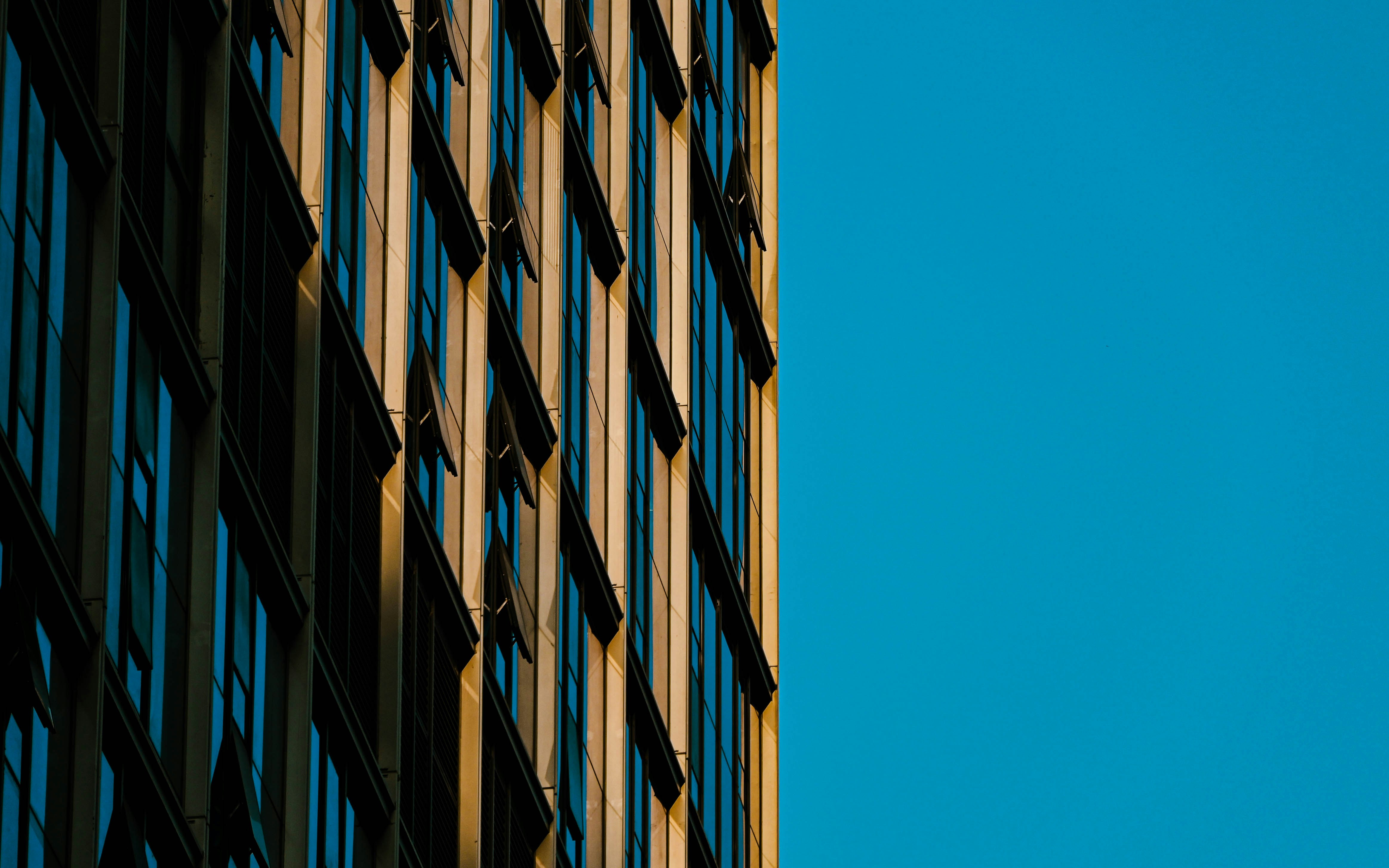 A tall building with lots of windows next to a blue sky photo – Free ...