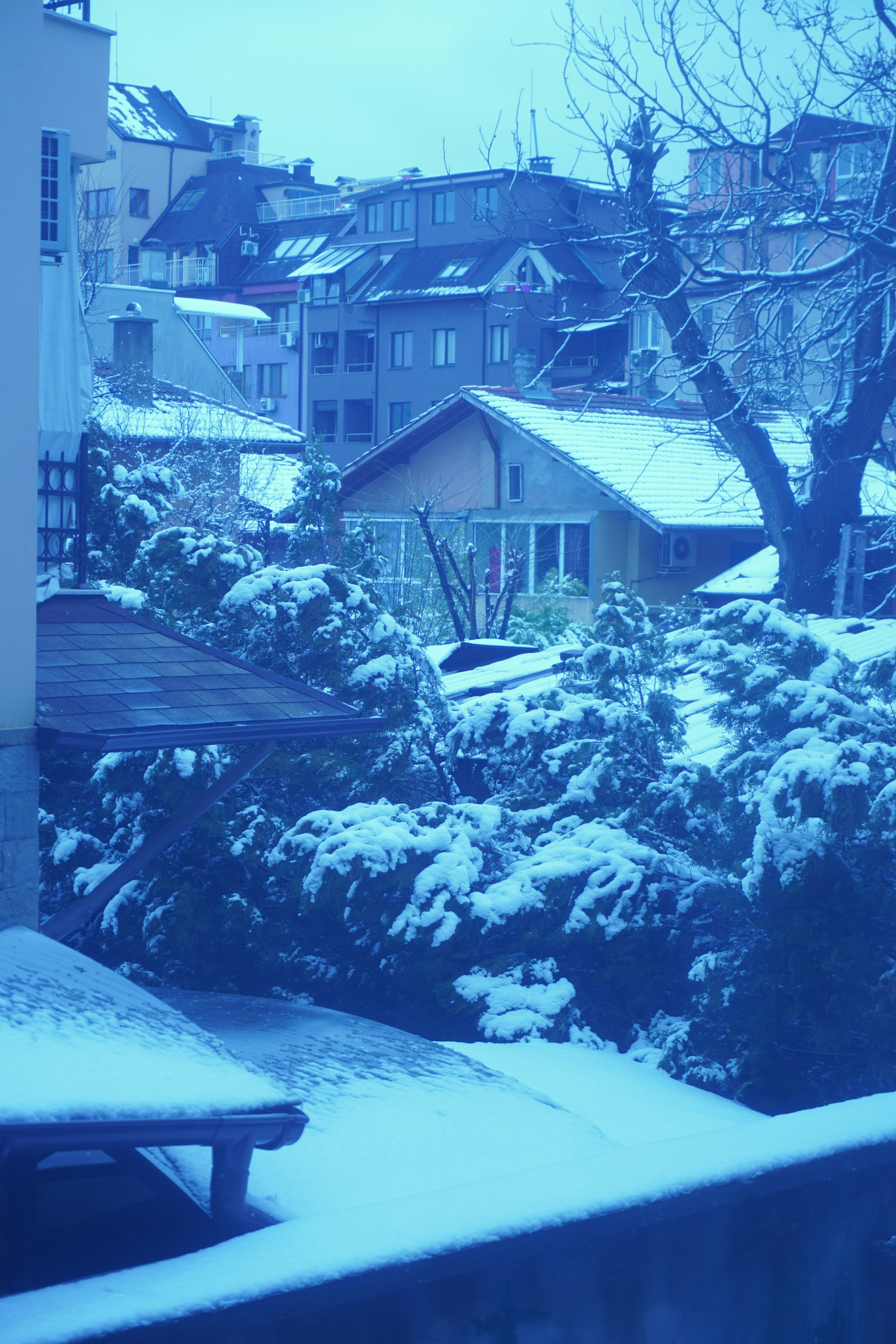 a snow covered park bench in front of a row of houses