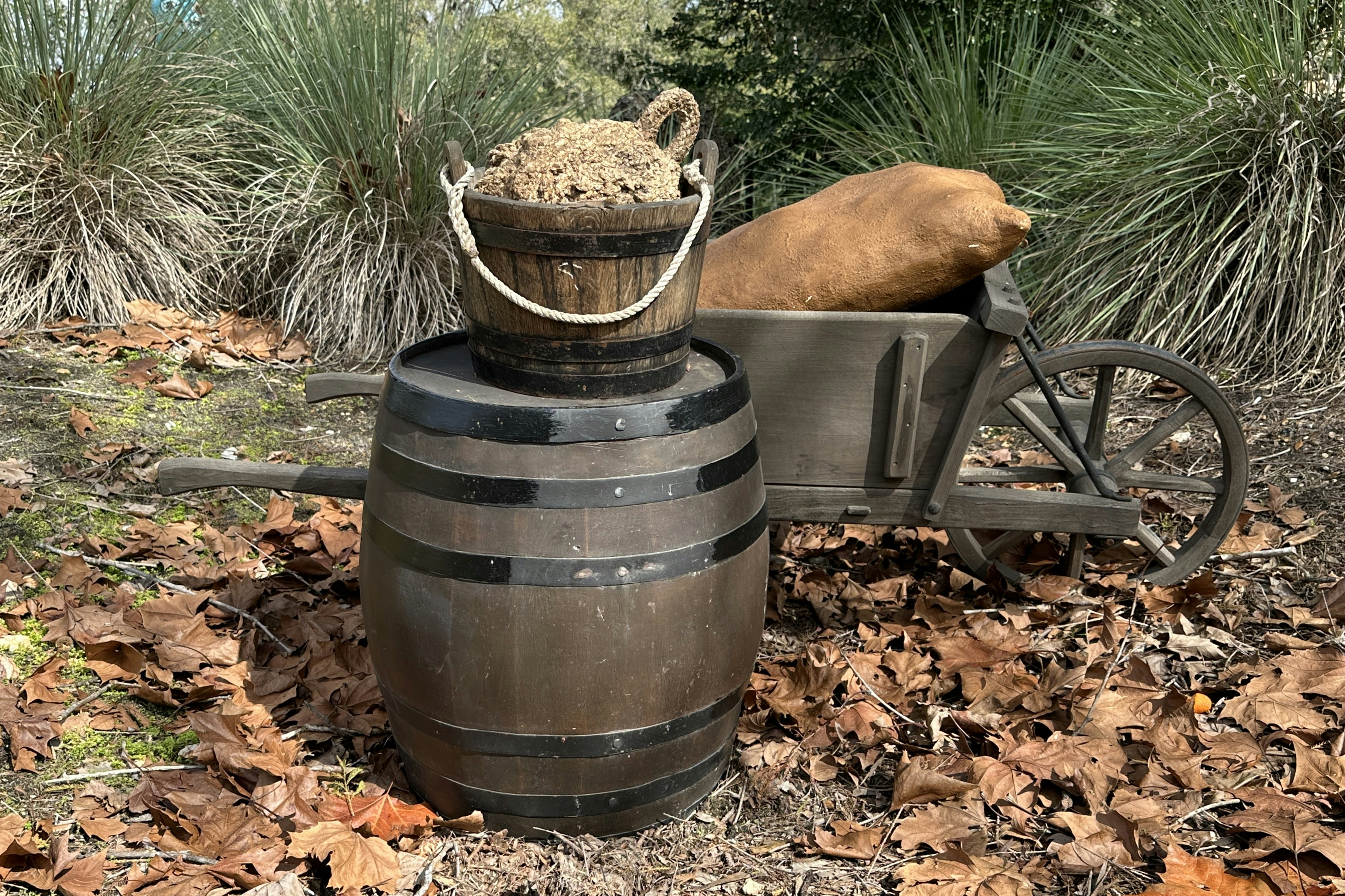 A dog is sitting in a barrel next to a wheelbarrow photo – Free Wheel ...