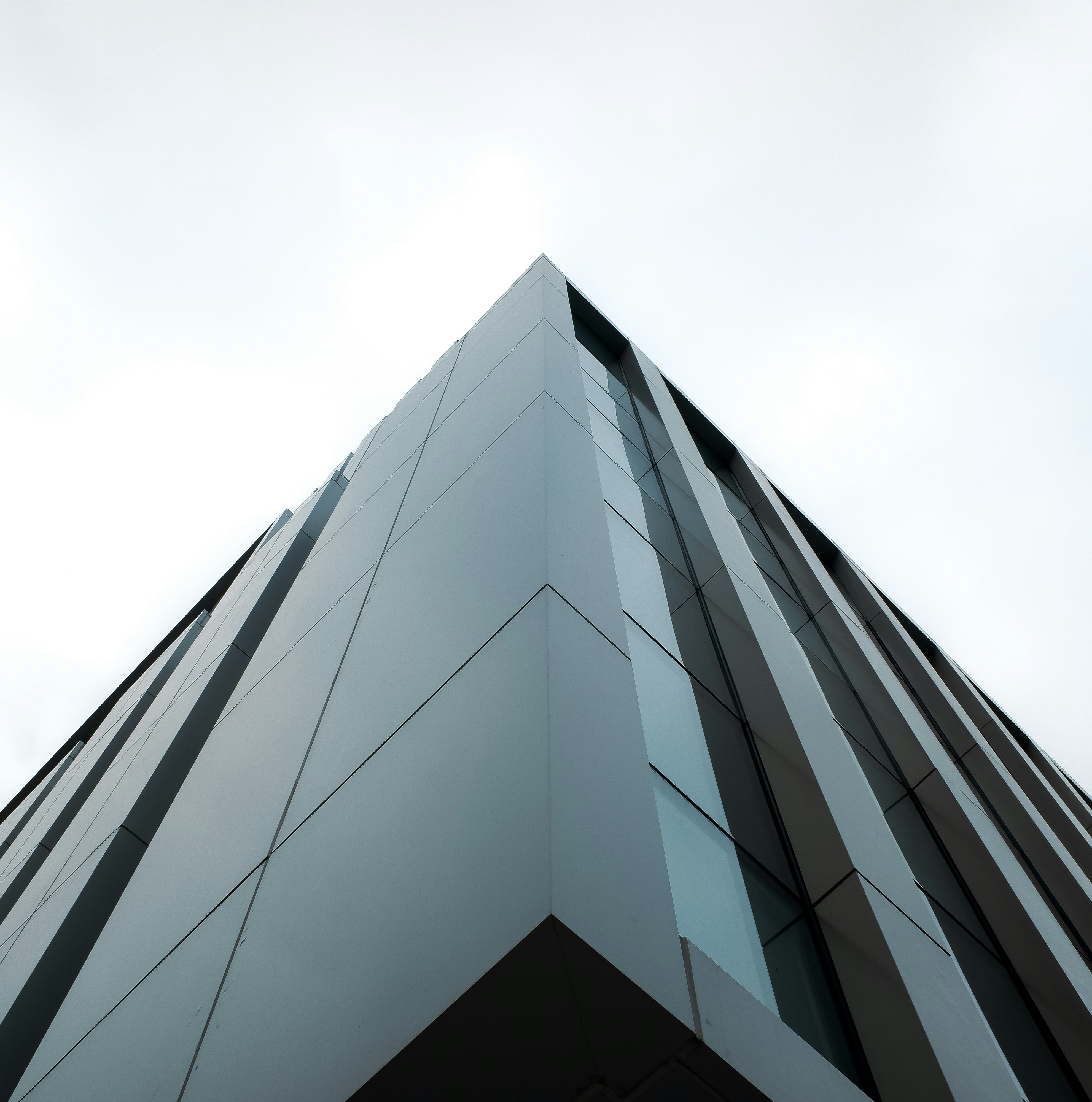 Modern building facade with sharp angles against a cloudy sky.