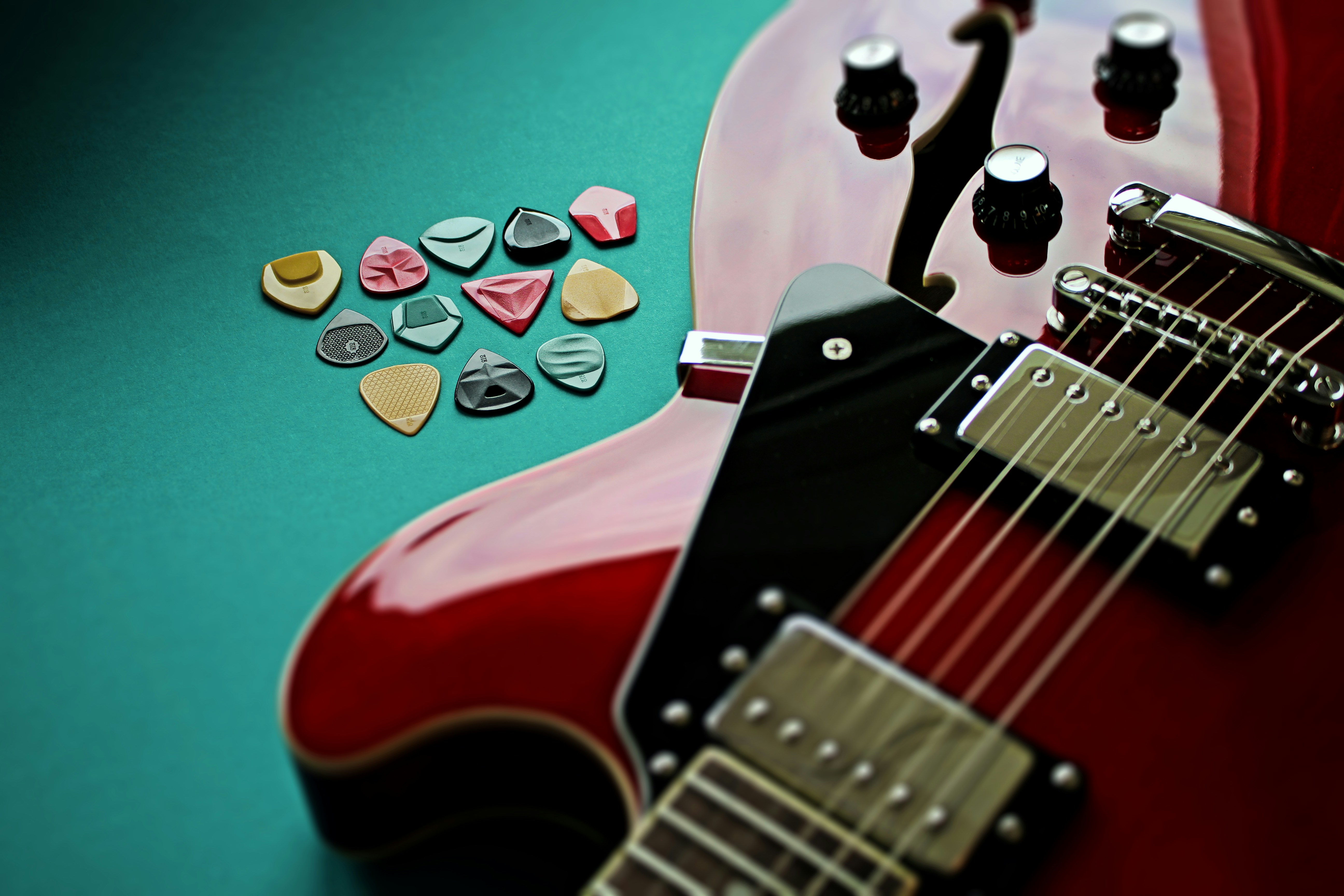 A red guitar with a guitar picker next to it photo – Free Guitar Image ...