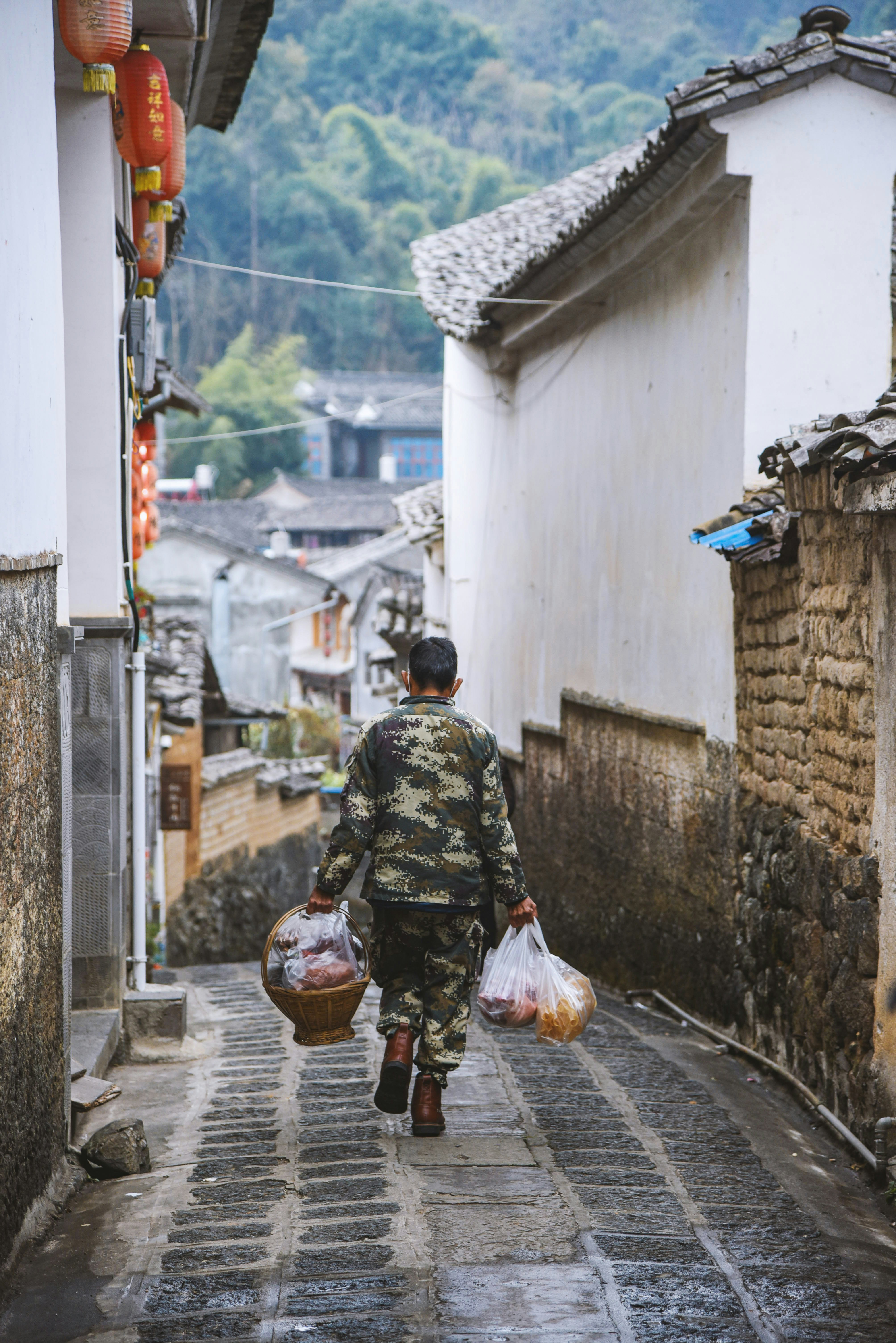 A man walking down a street carrying bags of food photo – Free Heshun ...