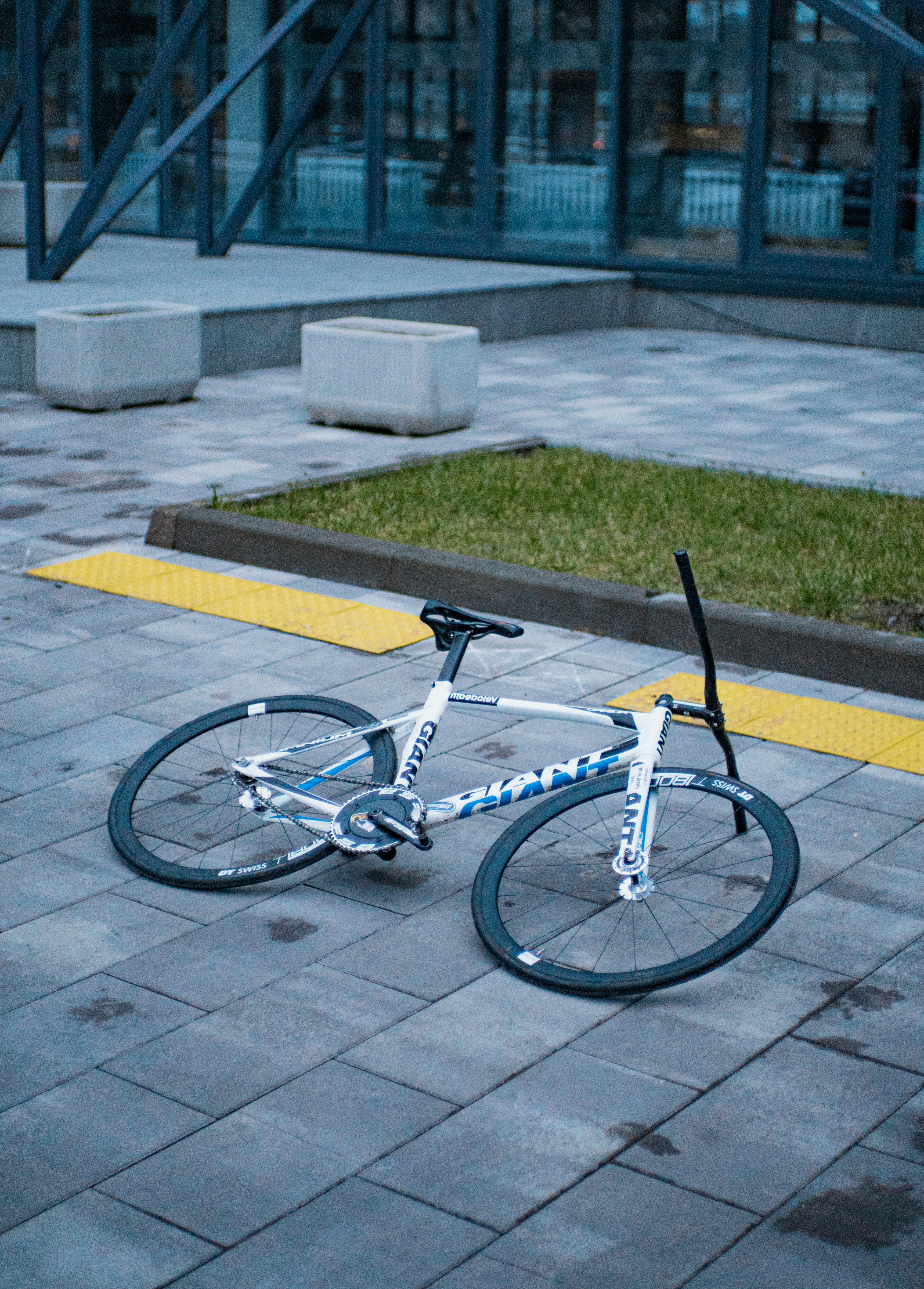 A white and blue bike parked on a sidewalk photo – Free Cycling Image ...