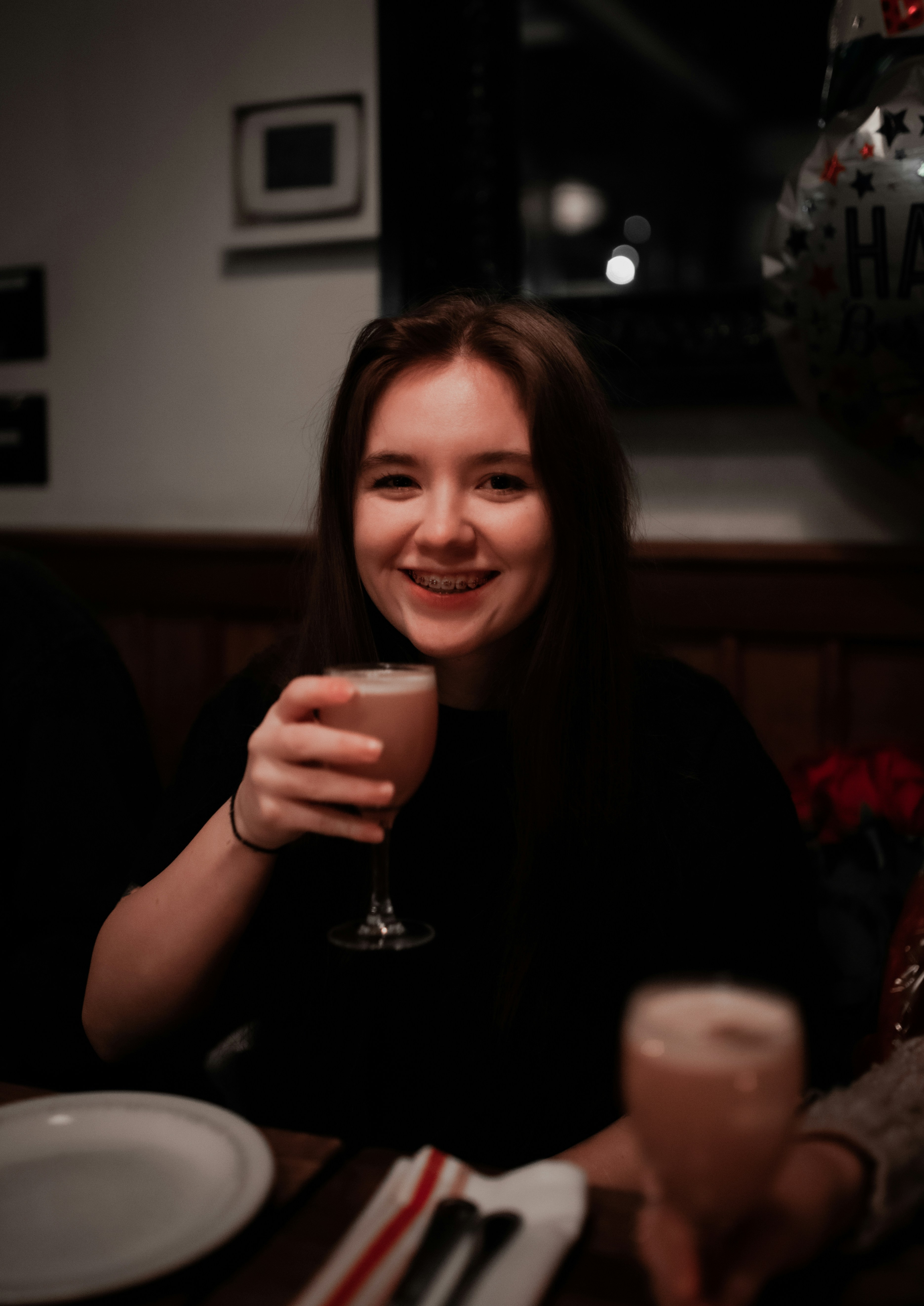 Amber-lit Toast: A Friendly Smile and Pink Cocktail in a Cozy Celebration