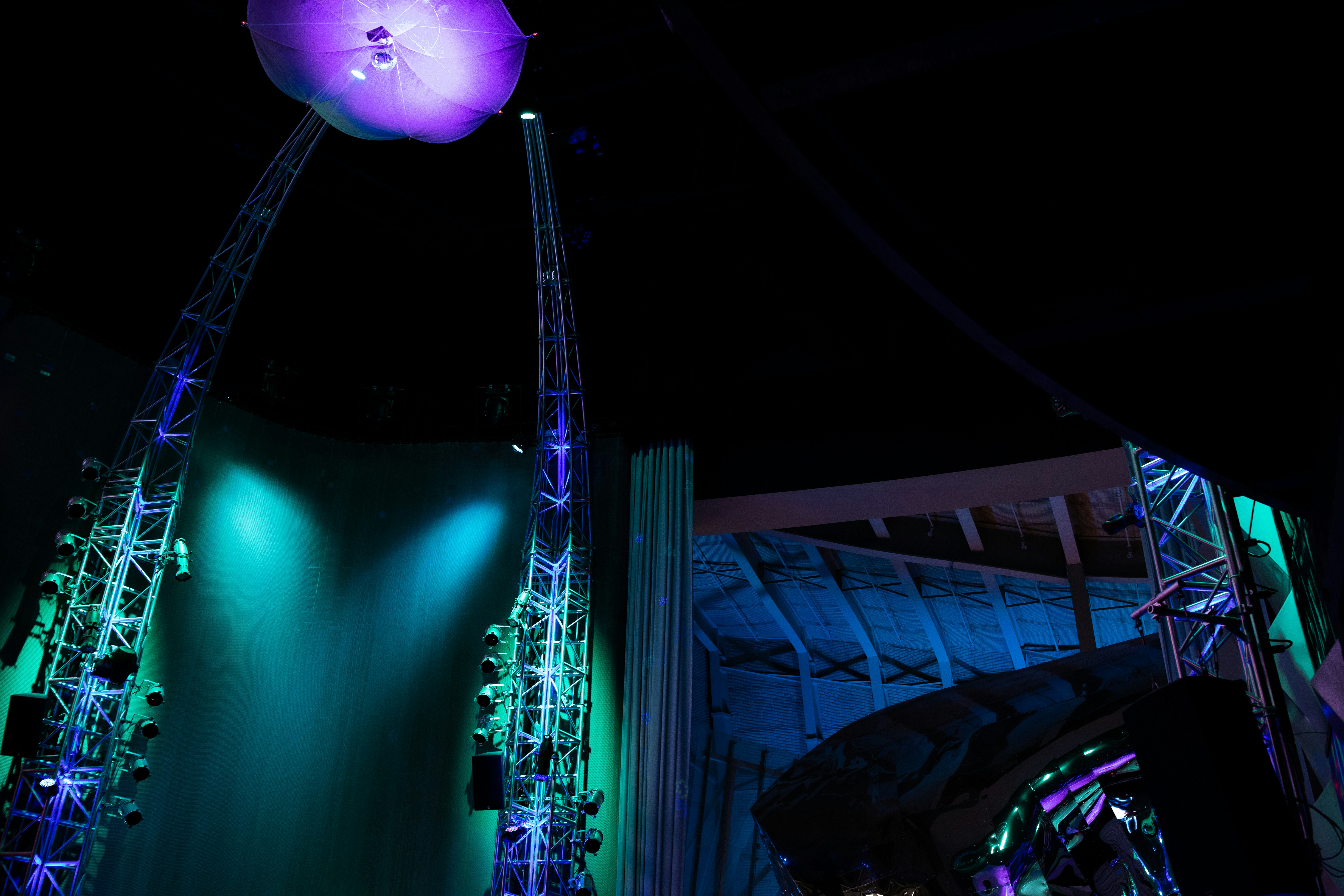 Violet Orb Hovers Above Neon-Tinted Stage Trusses