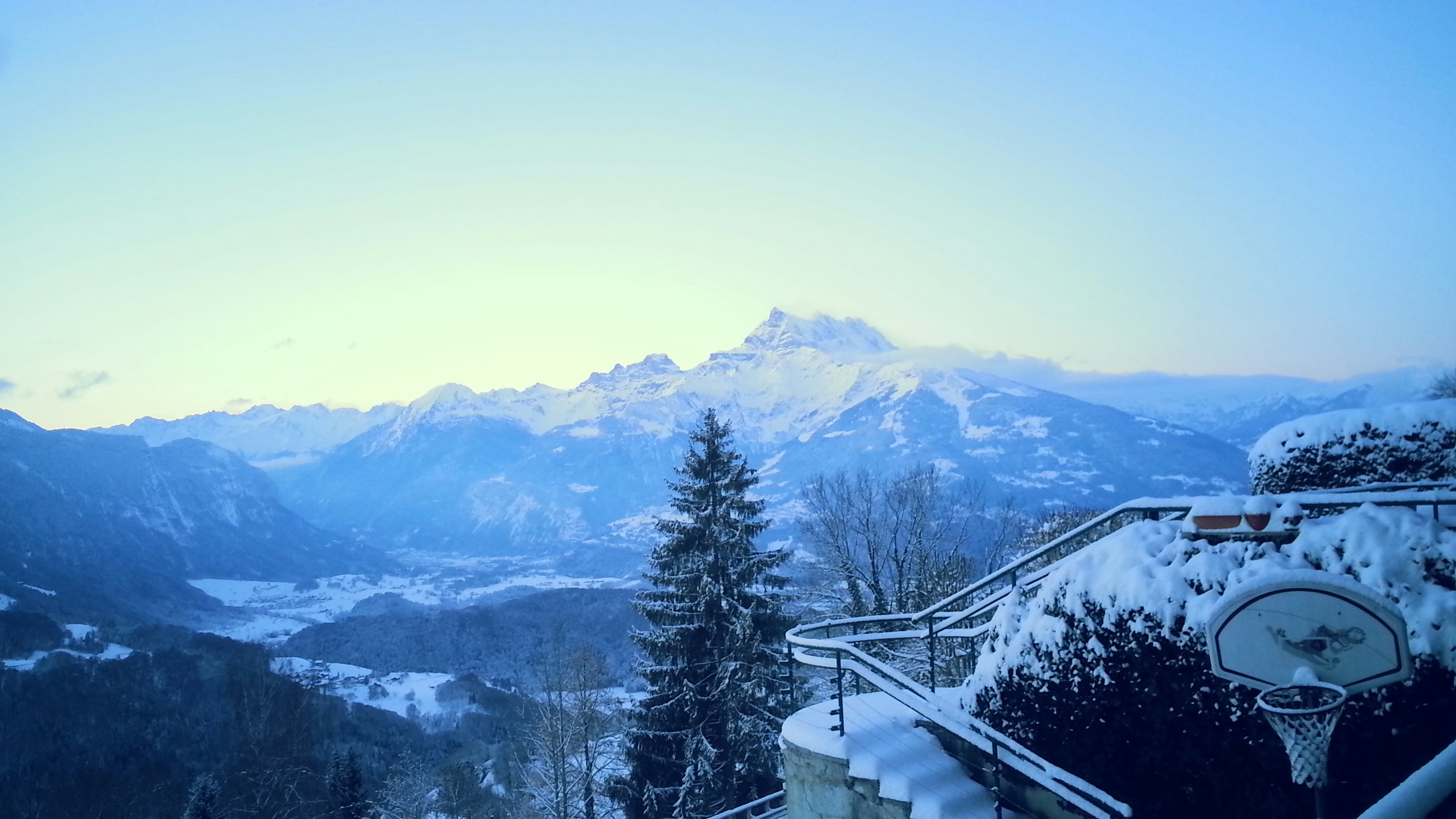 Blue Hour Alps: Snow-Capped Peaks Framed by a Balcony and a Foreground Hoop