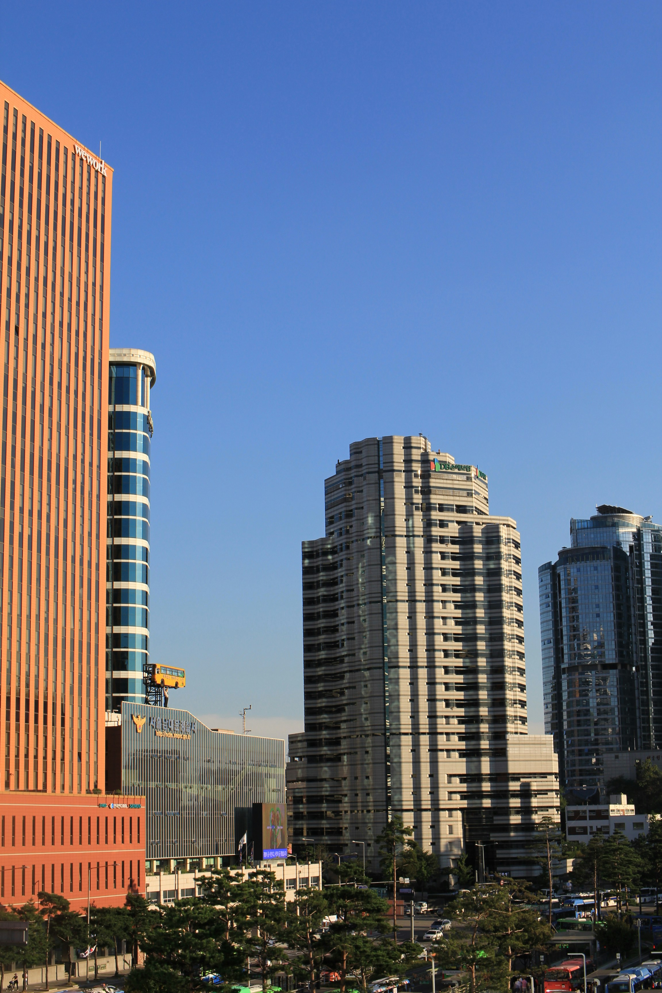 Modern skyscrapers rise against a clear blue sky, showcasing a blend of architectural styles in a bustling urban landscape.