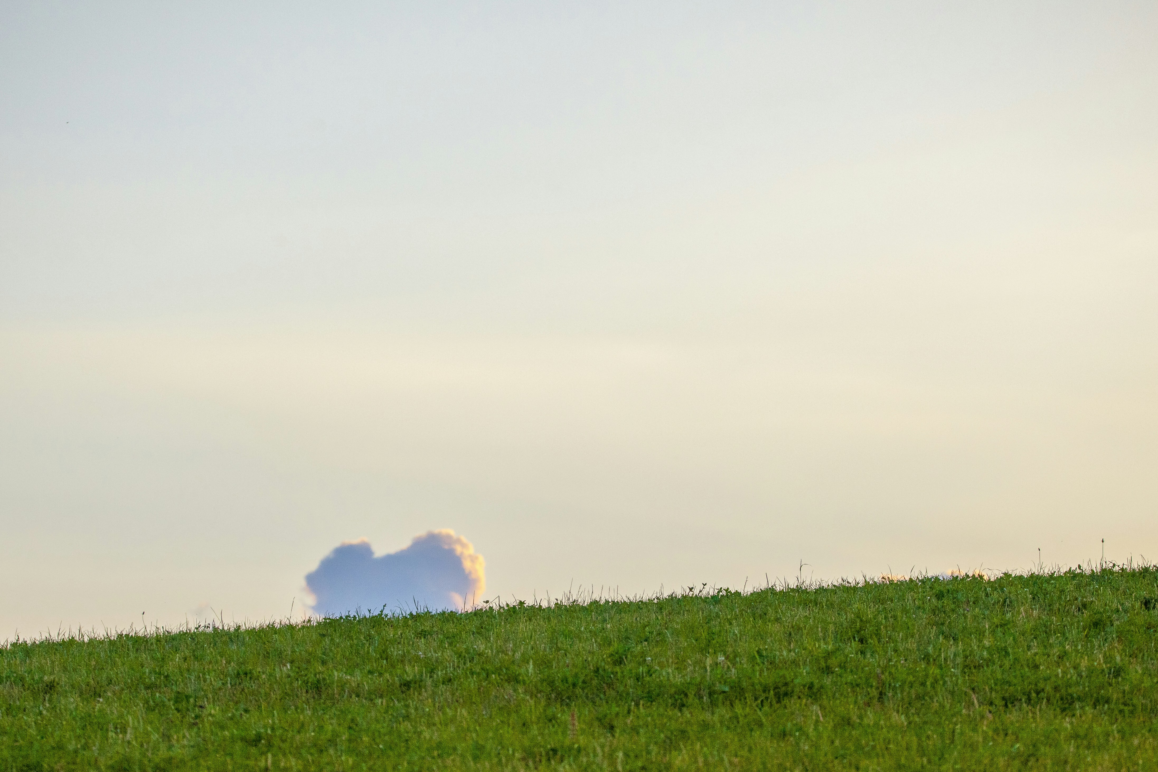 A single cloud in the sky above a grassy hill photo – Free Sky Image on ...