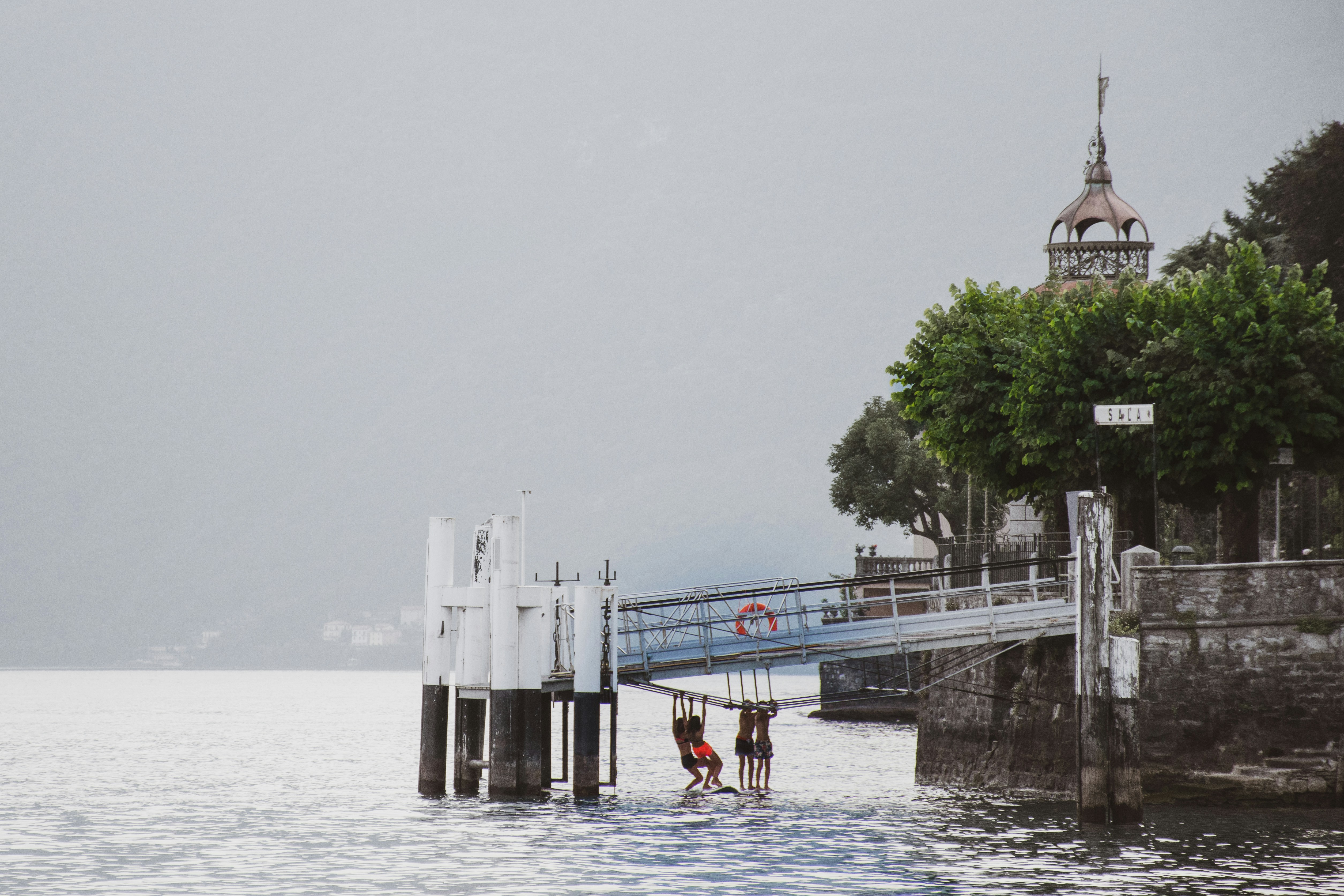 Three Figures at the Narrow Pier: Quiet Waterfront Moment by the Clock Tower