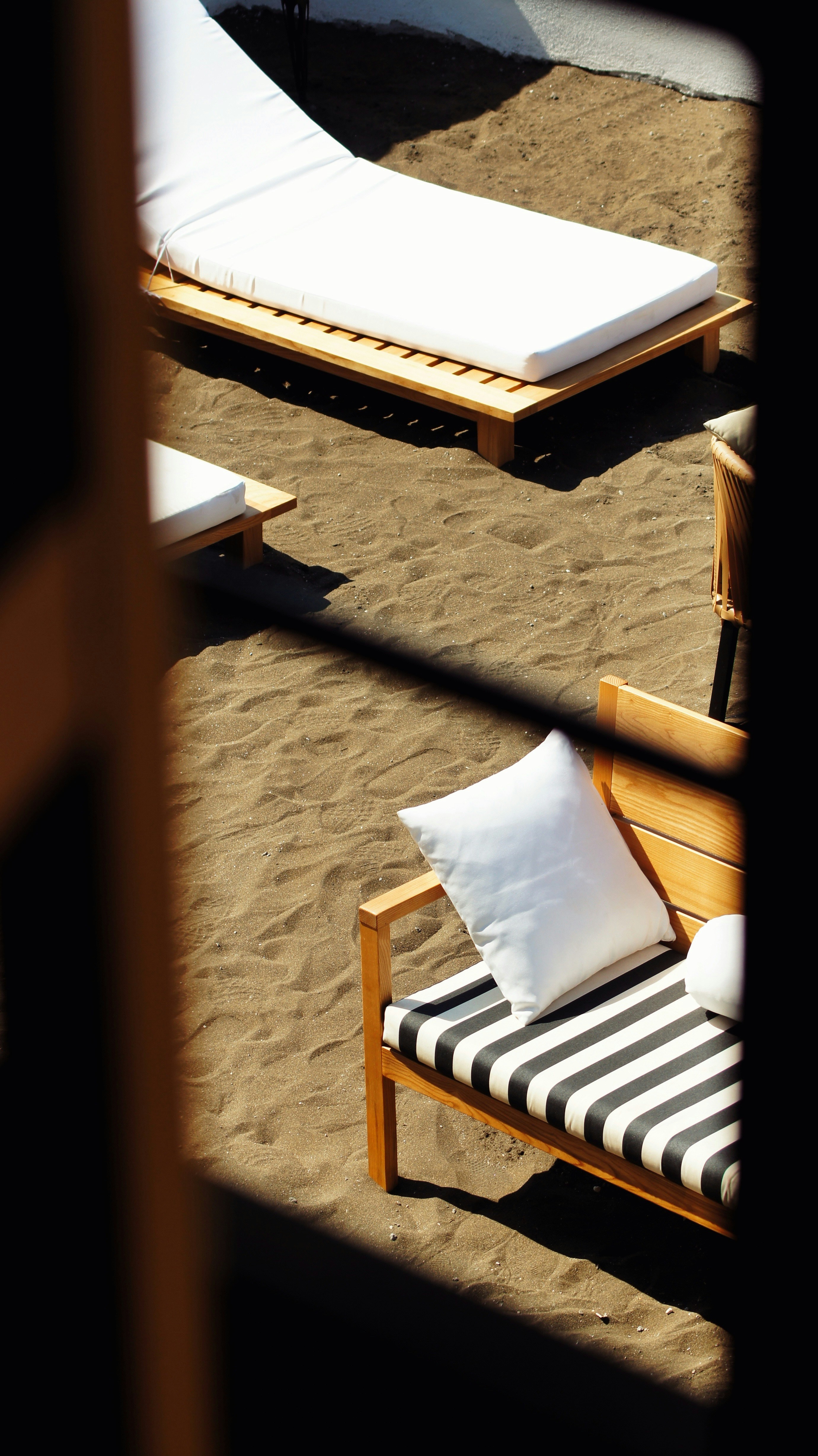 a couple of lounge chairs sitting on top of a sandy beach