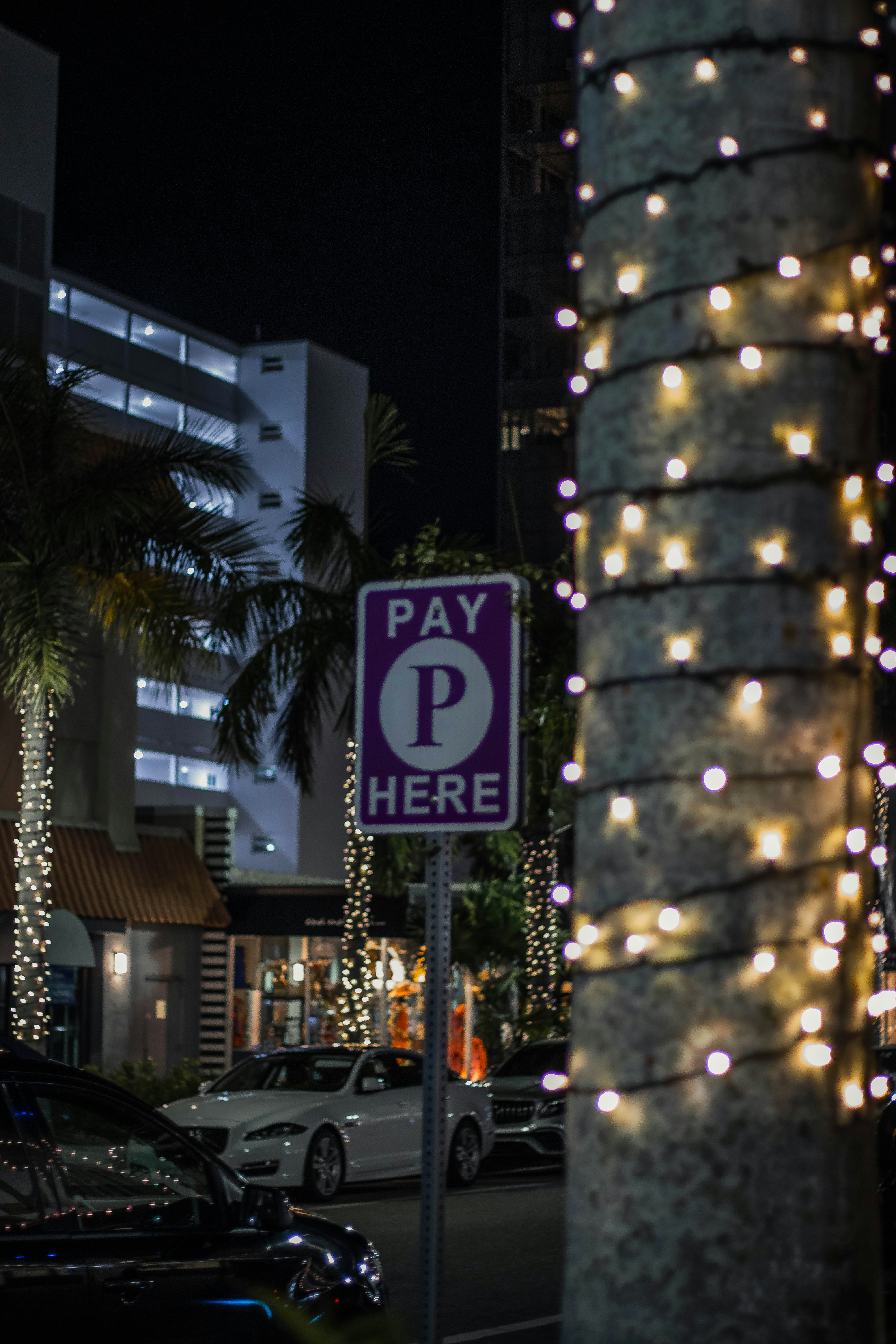 A purple pay here sign sitting on the side of a road photo – Free City ...