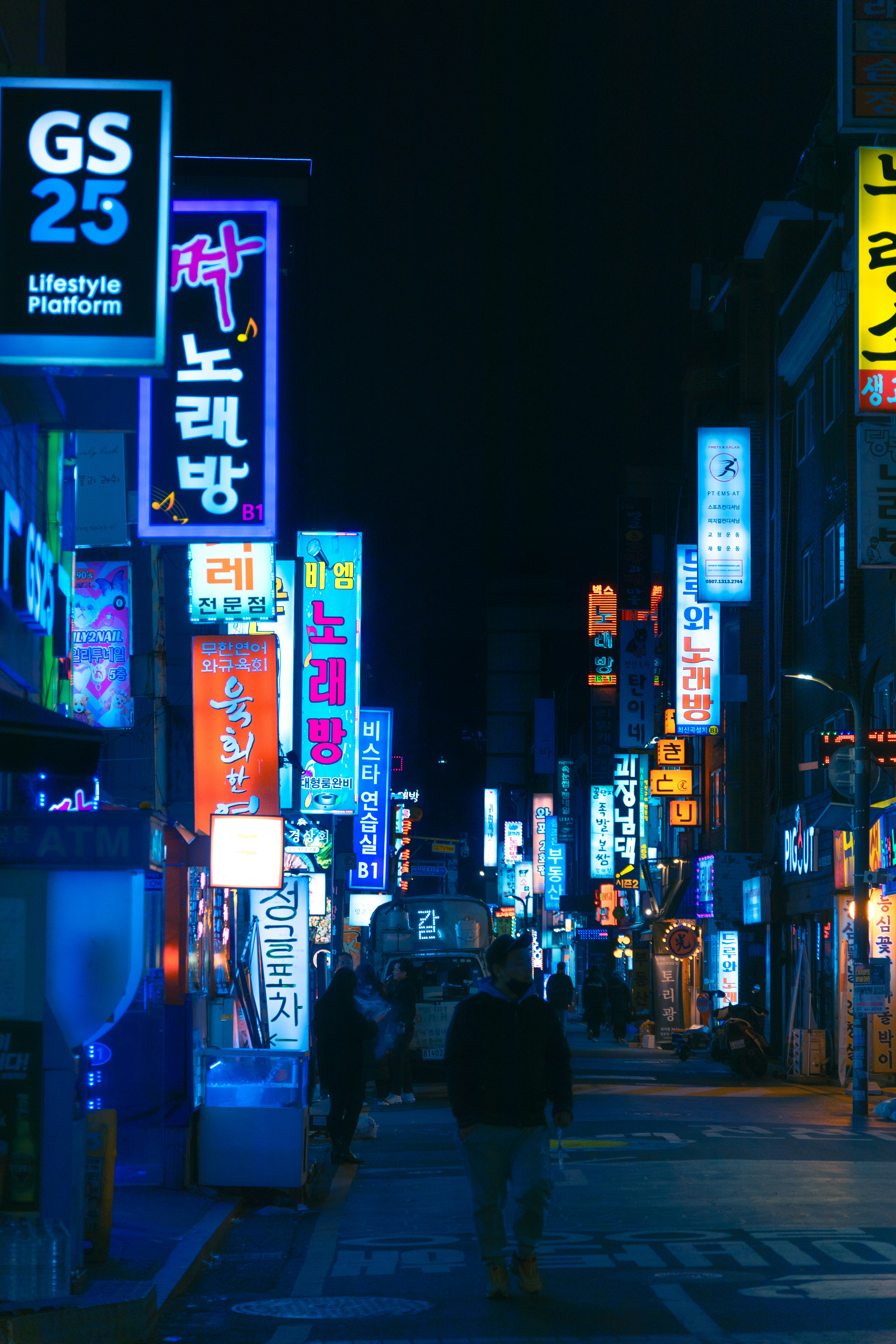 Vibrant neon signs illuminate a bustling street, showcasing the lively atmosphere of urban nightlife. Pedestrians navigate through the colorful displays.