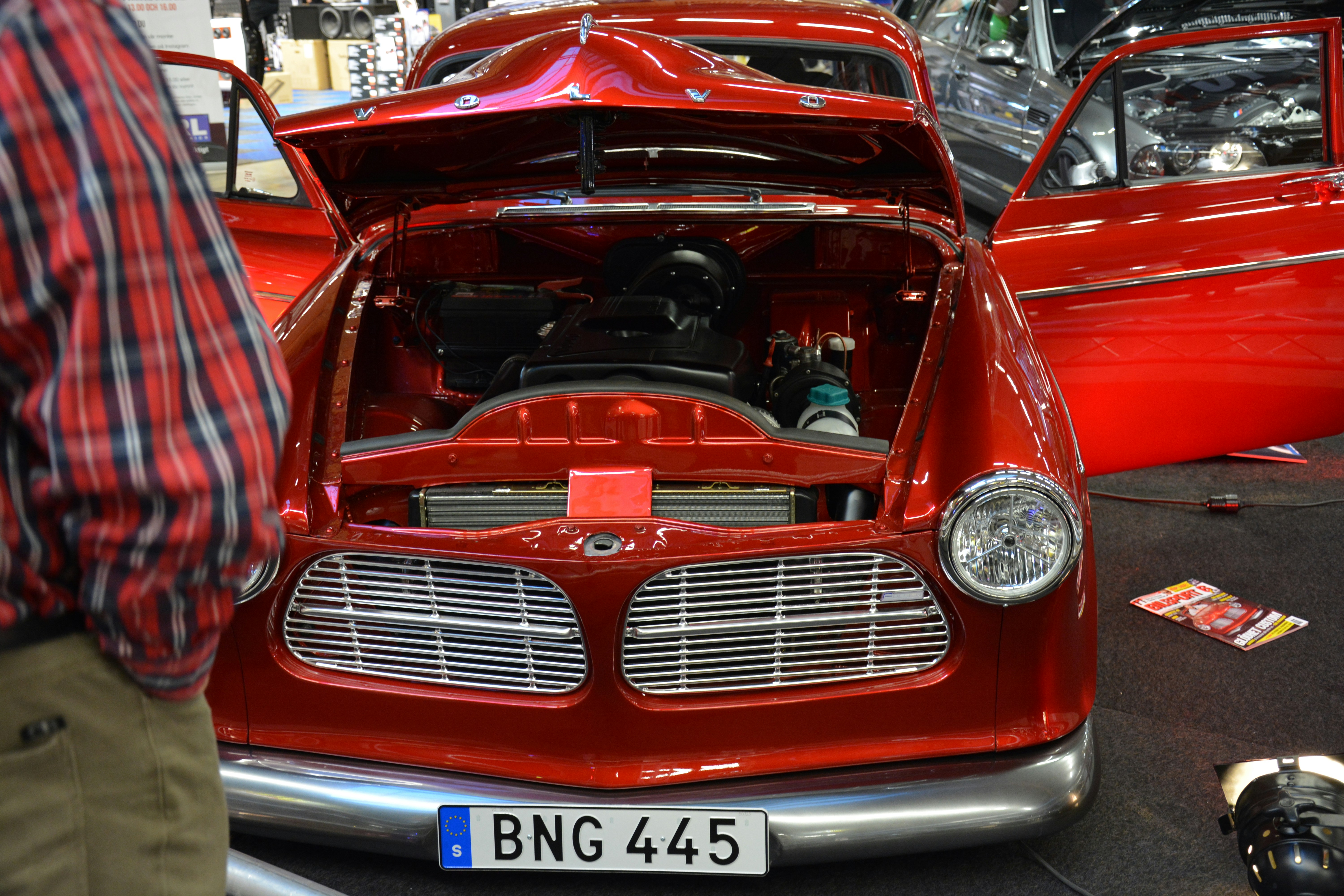 A man standing next to a red car in a garage photo – Free Image on Unsplash