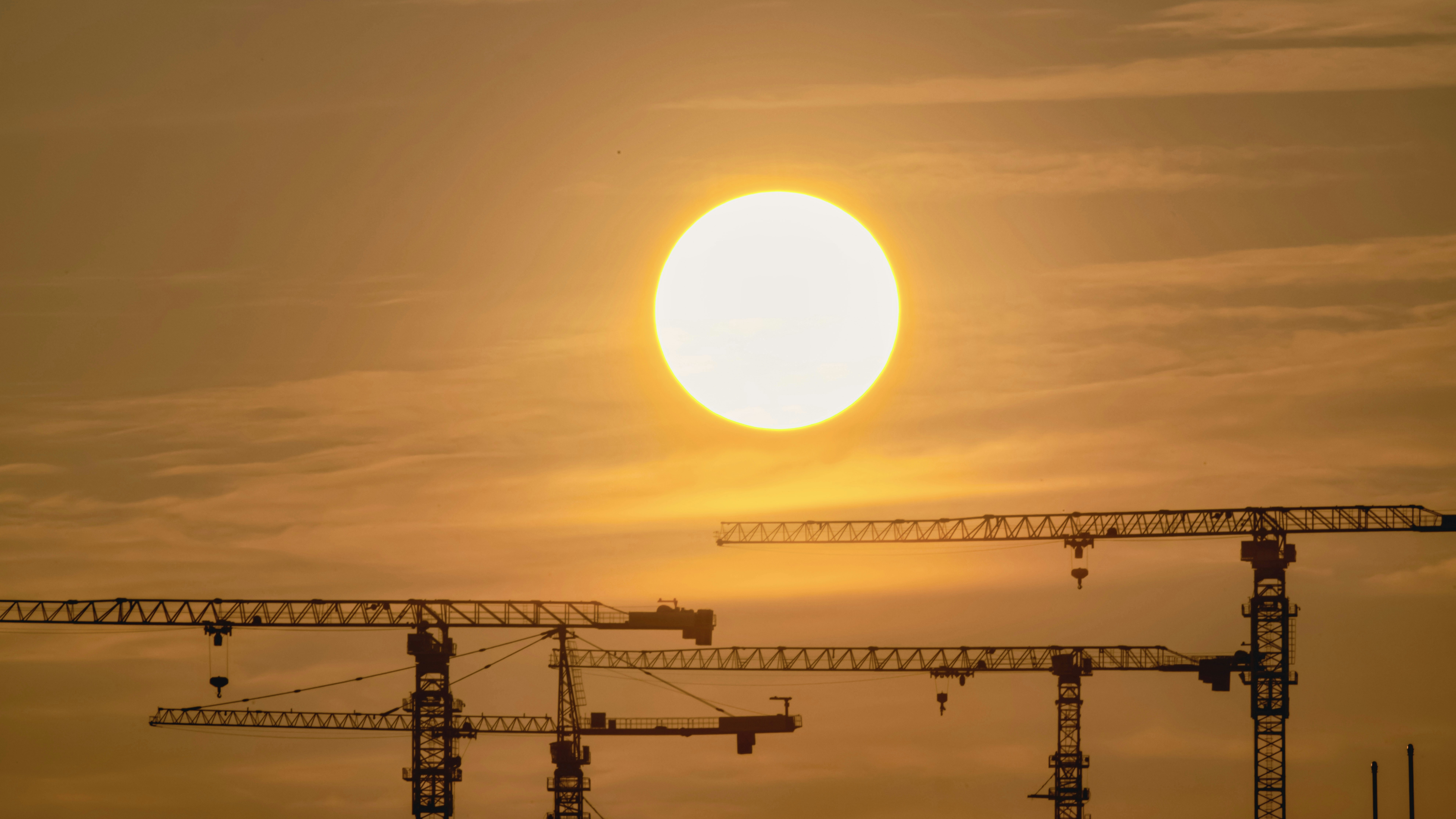 Molten Sun Over an Industrial Horizon: Crane Silhouettes