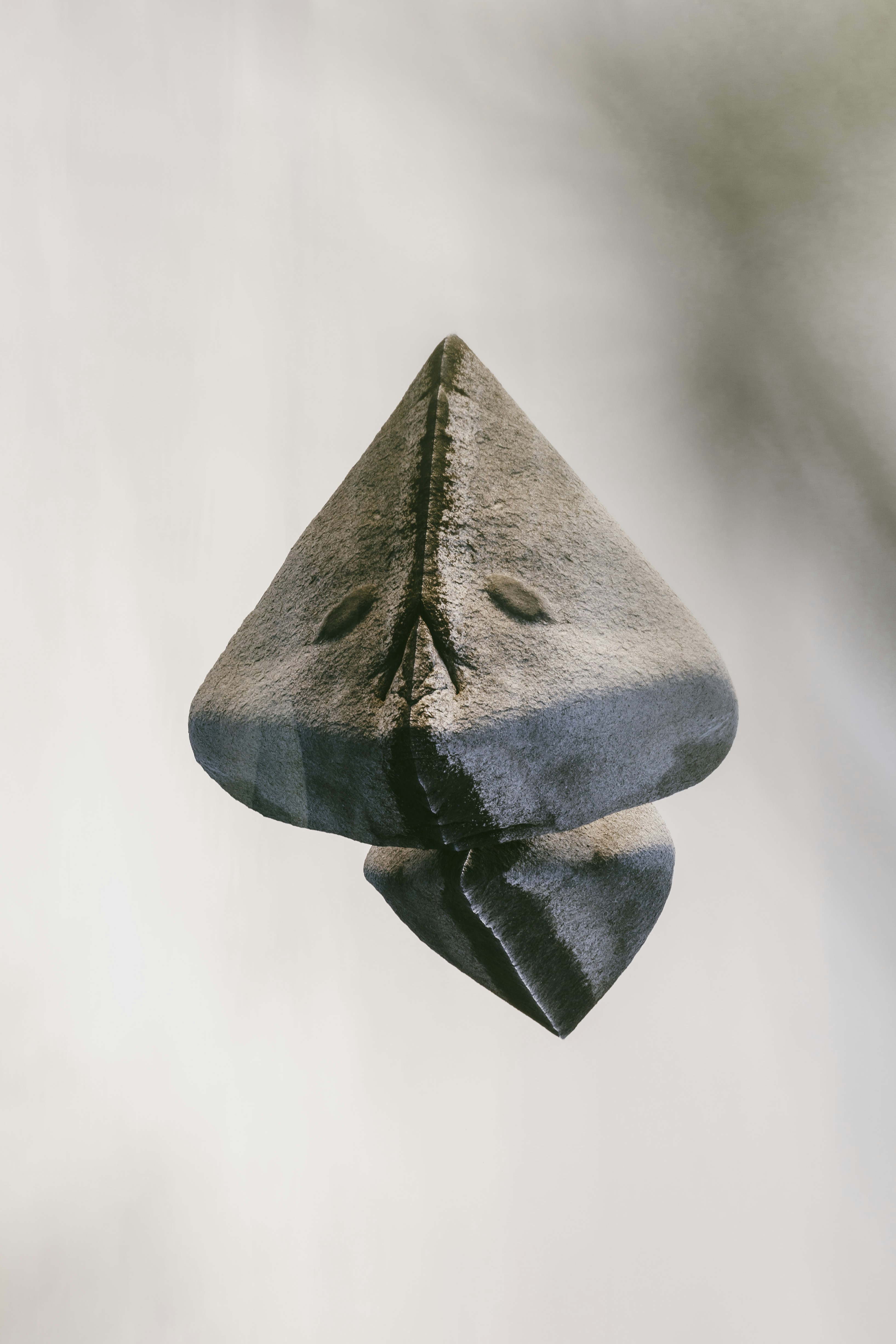 Suspended Stone Finial: A Weathered Pyramid Hovering in Gentle Light