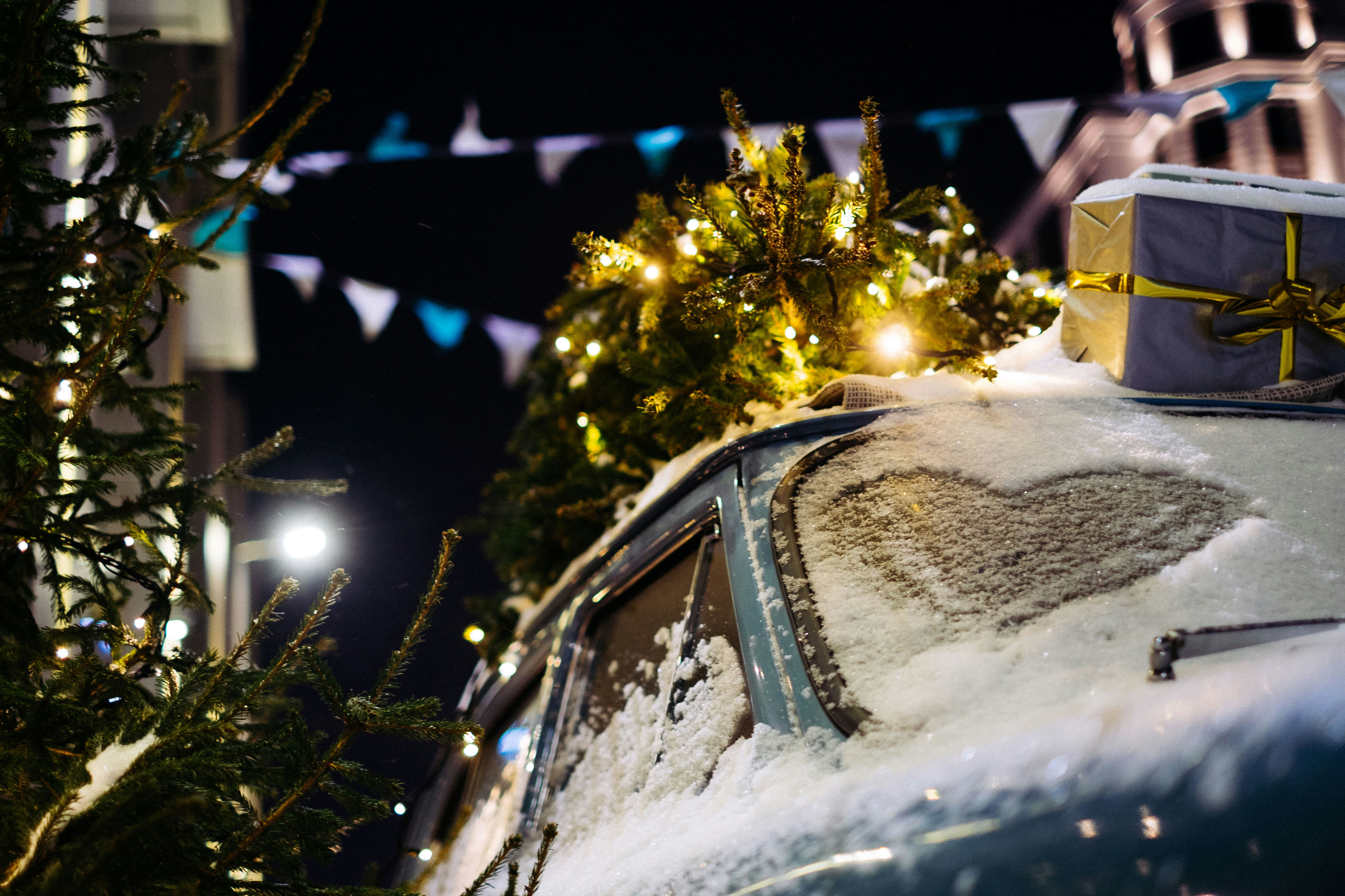 Snow-kissed vintage car crowned with gifts under festive lights