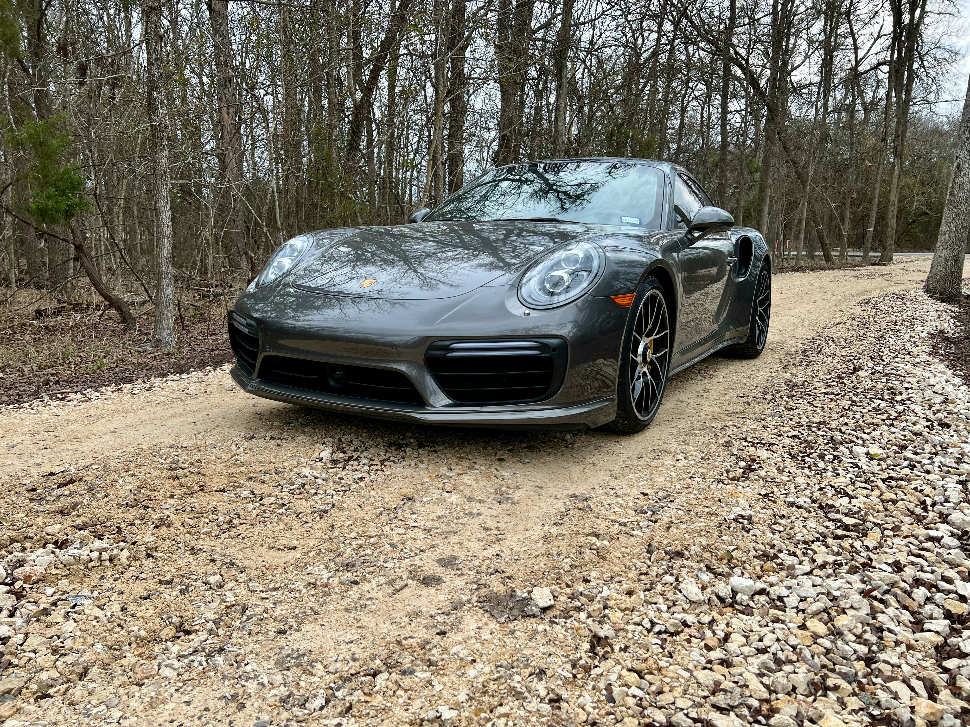 Grey Porsche on a Rugged Forest Gravel Road