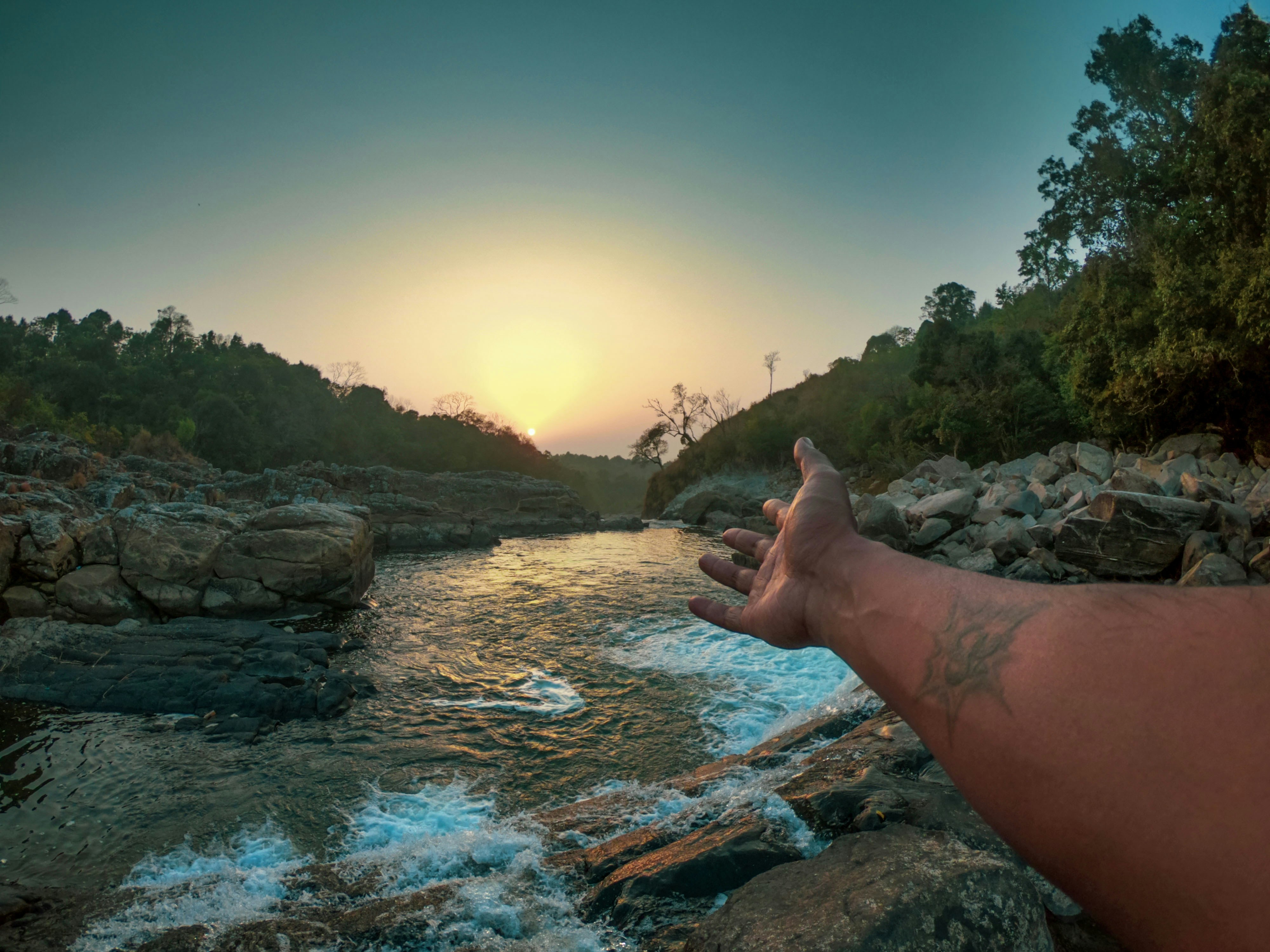 Toward the Sunset: An Outstretched Arm Over a Rocky River Gorge