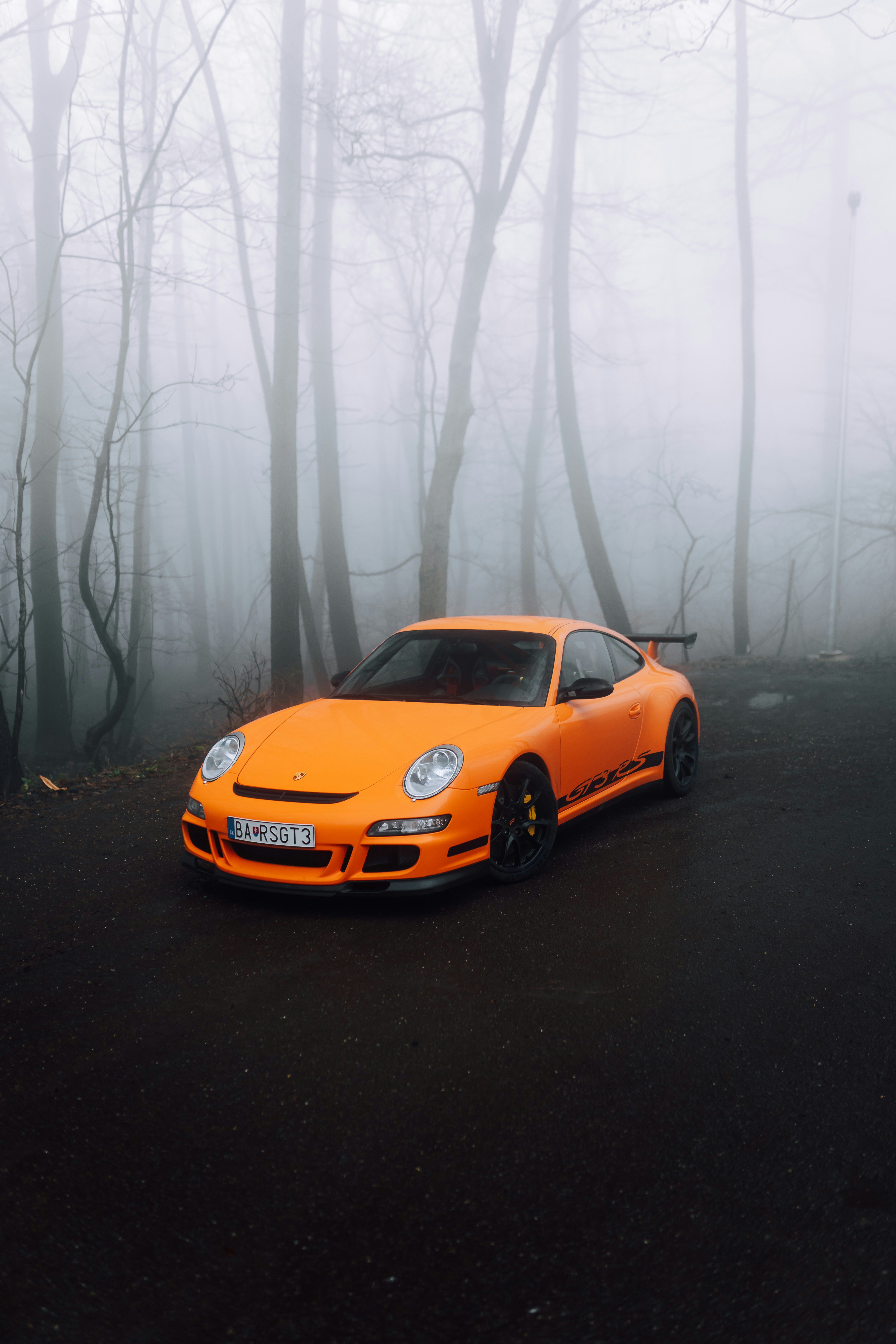 an orange sports car parked on a foggy road