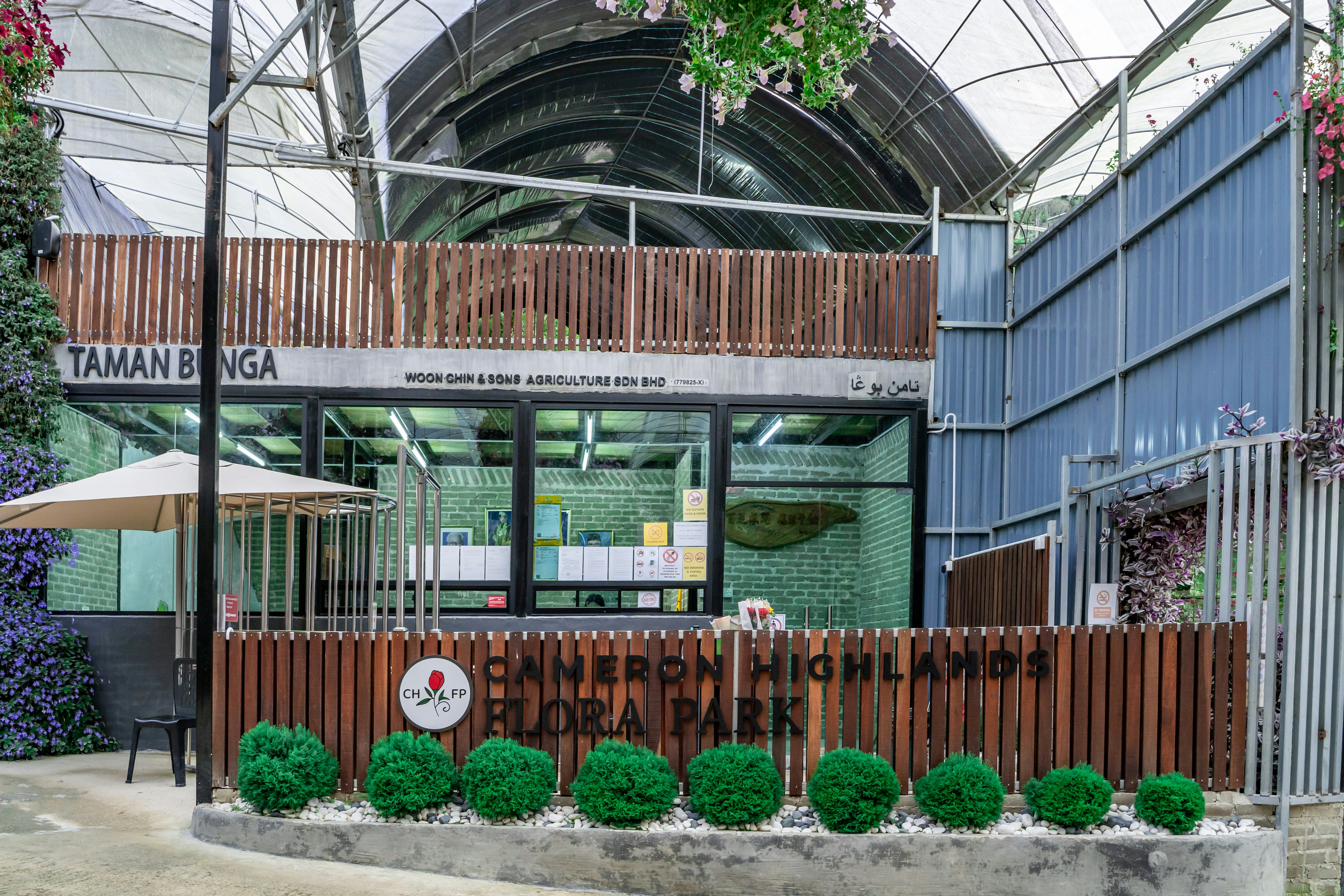 a building with a wooden fence and green plants in front of it