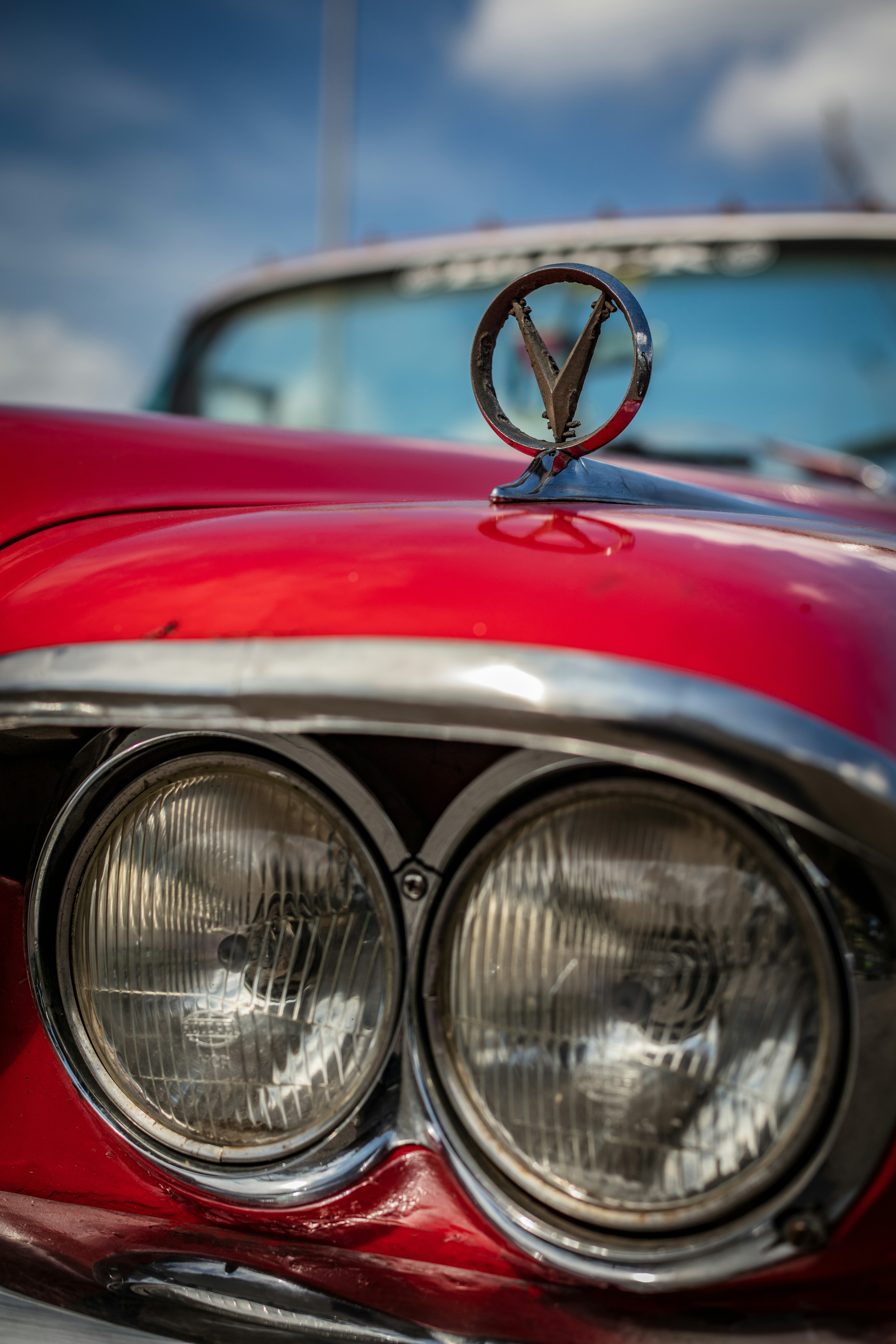 V-Emblem in Crimson: Close-Up of a Vintage Car Hood Ornament