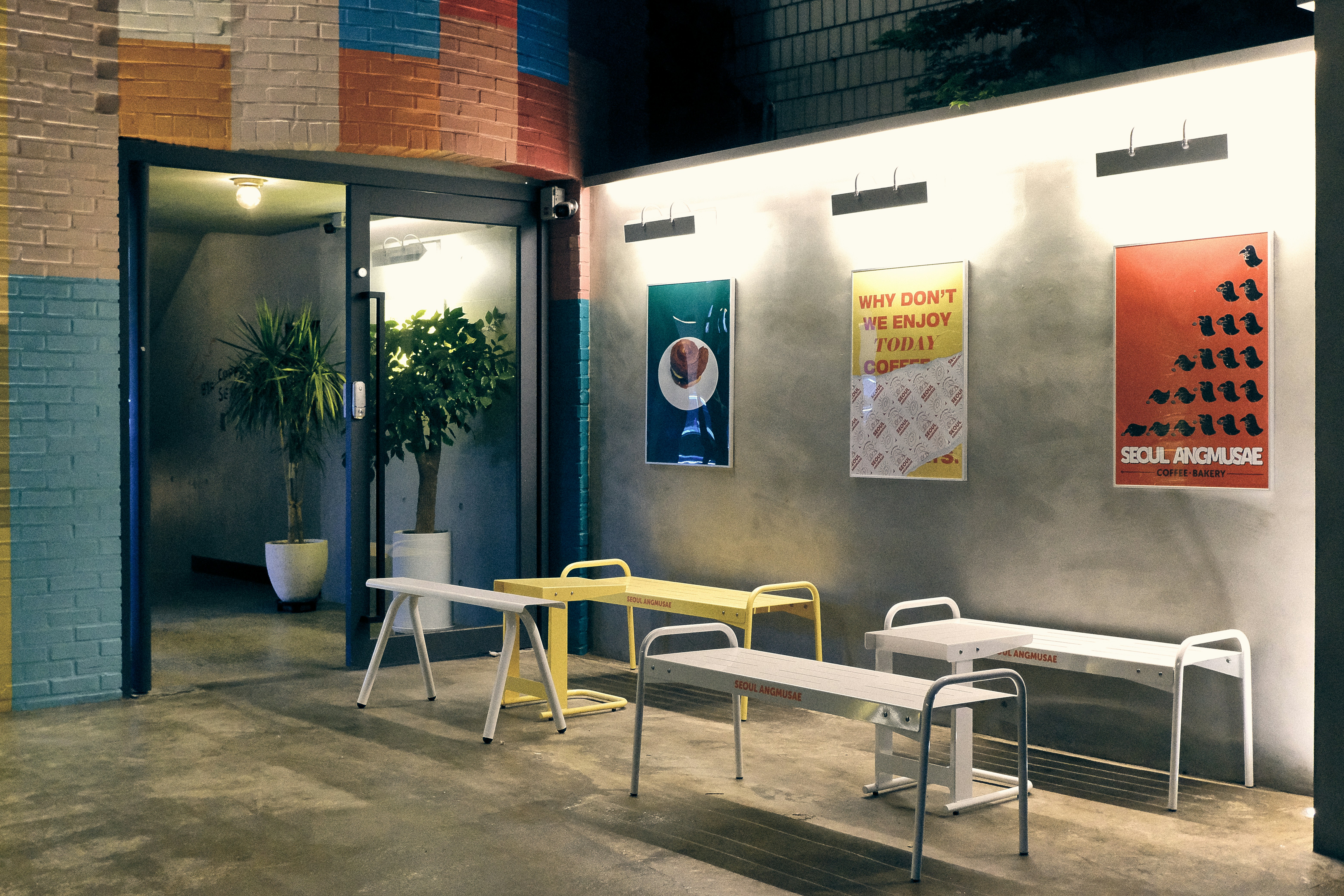Modern hallway with colorful posters and minimalist benches under warm lighting.