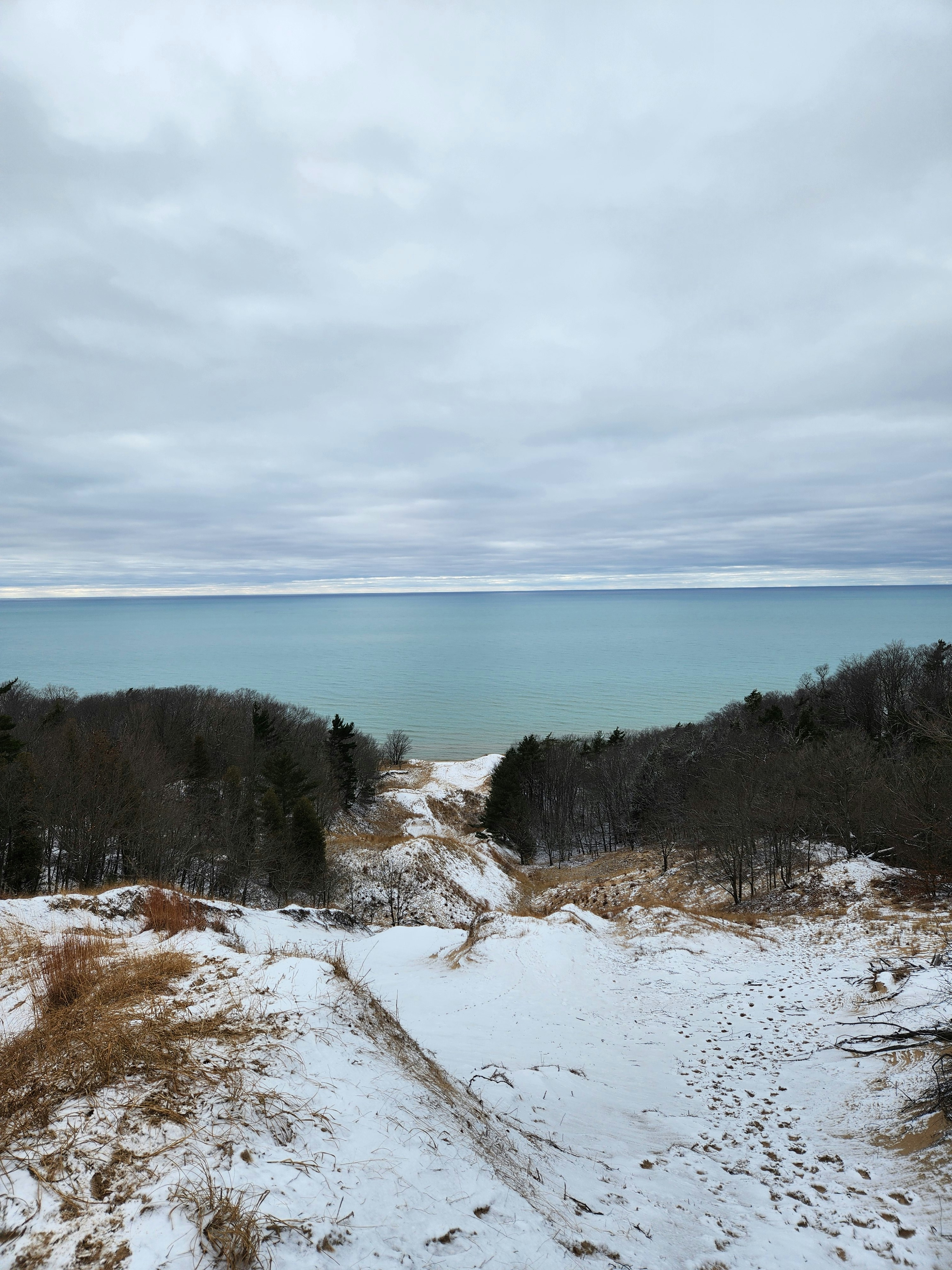 Snow-dusted dunes lead to a calm turquoise horizon