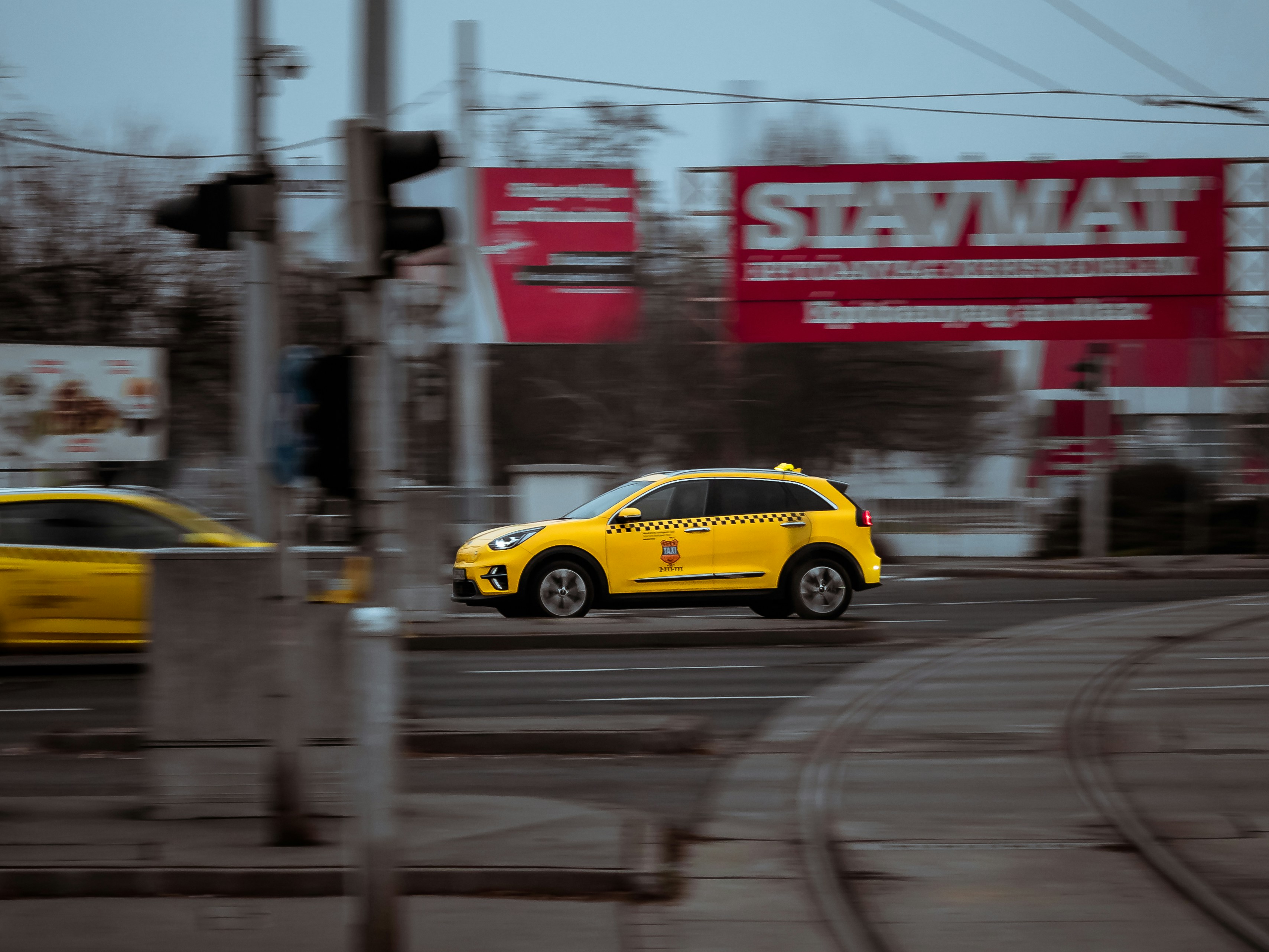 Yellow Taxi in a Blurred City Intersection Under Bold Red Signage