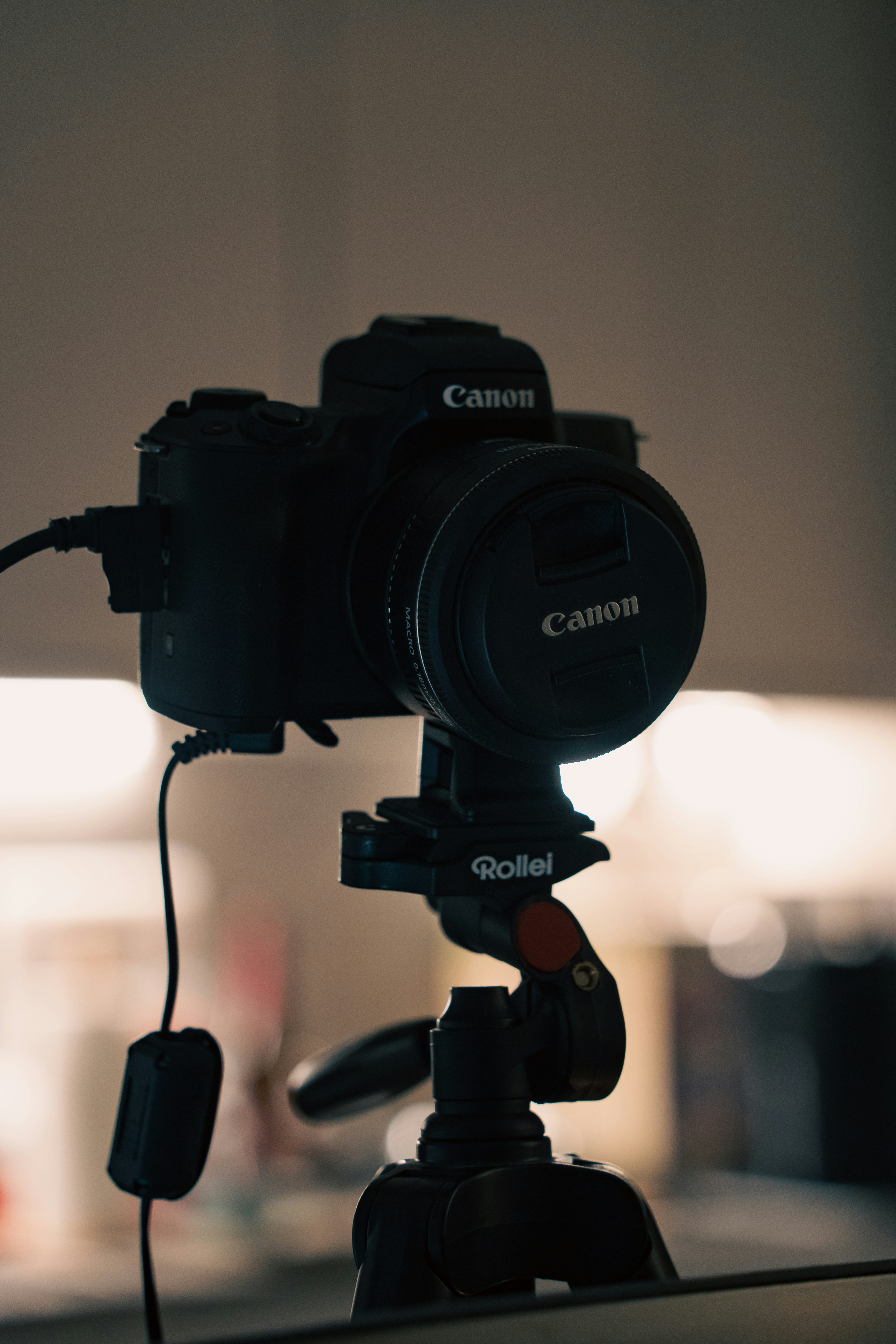 A Canon camera mounted on a tripod, set against a softly lit background that hints at a creative workspace.