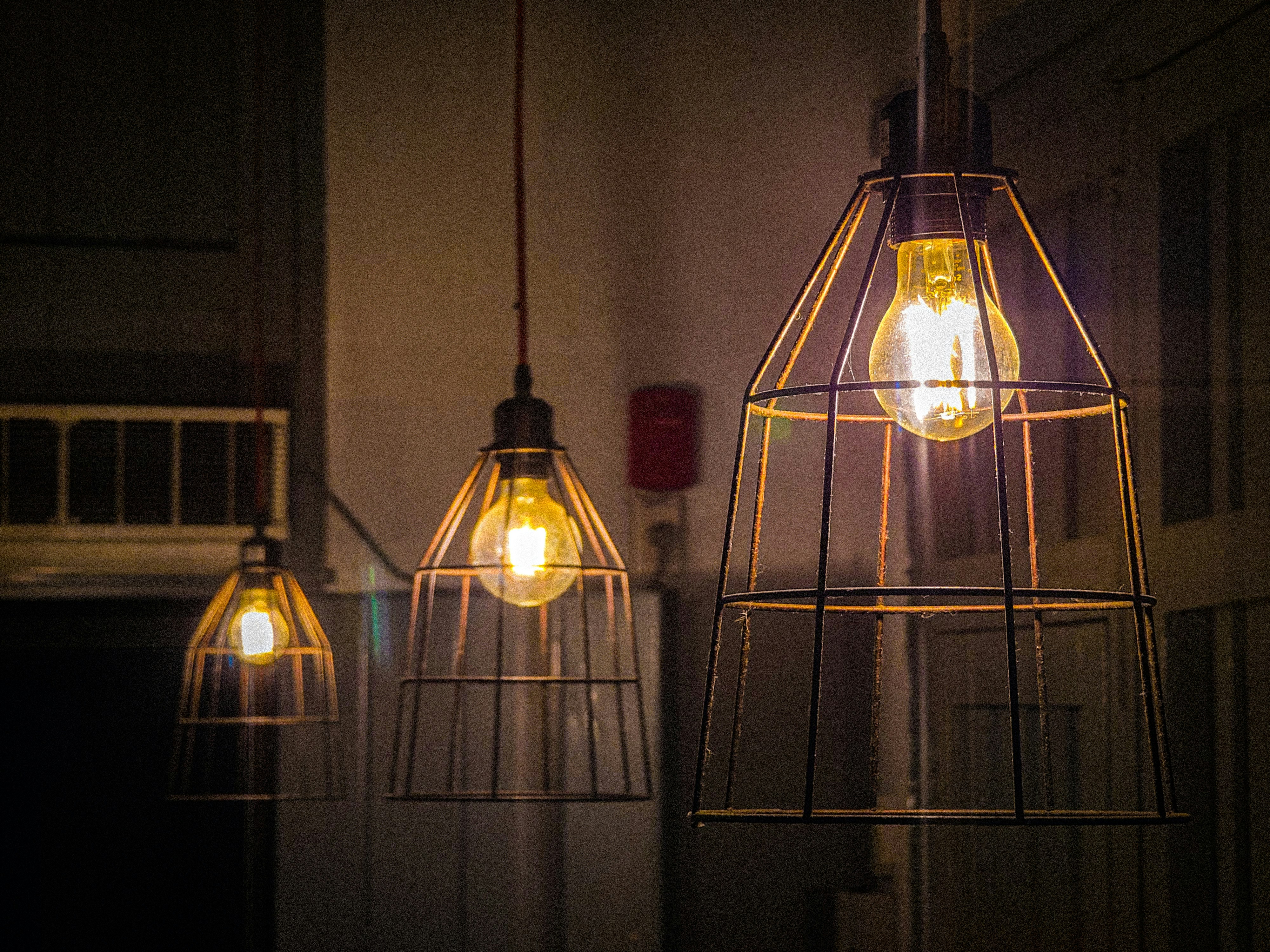 Warm Geometry: Three Pendant Lamps Casting Amber Glow in a Dim Studio