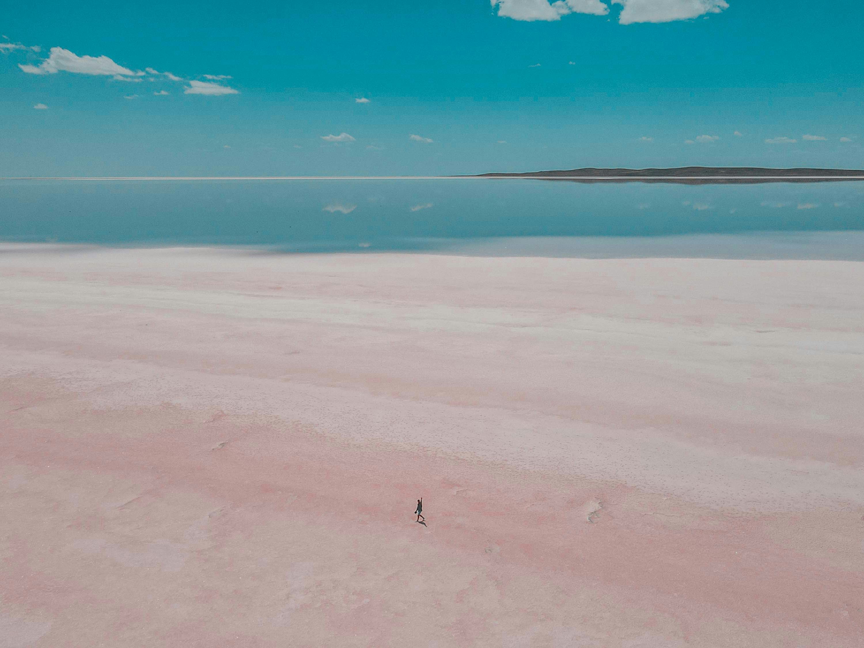 Pink Sands and Skyline: A Lone Figure on a Teal Horizon