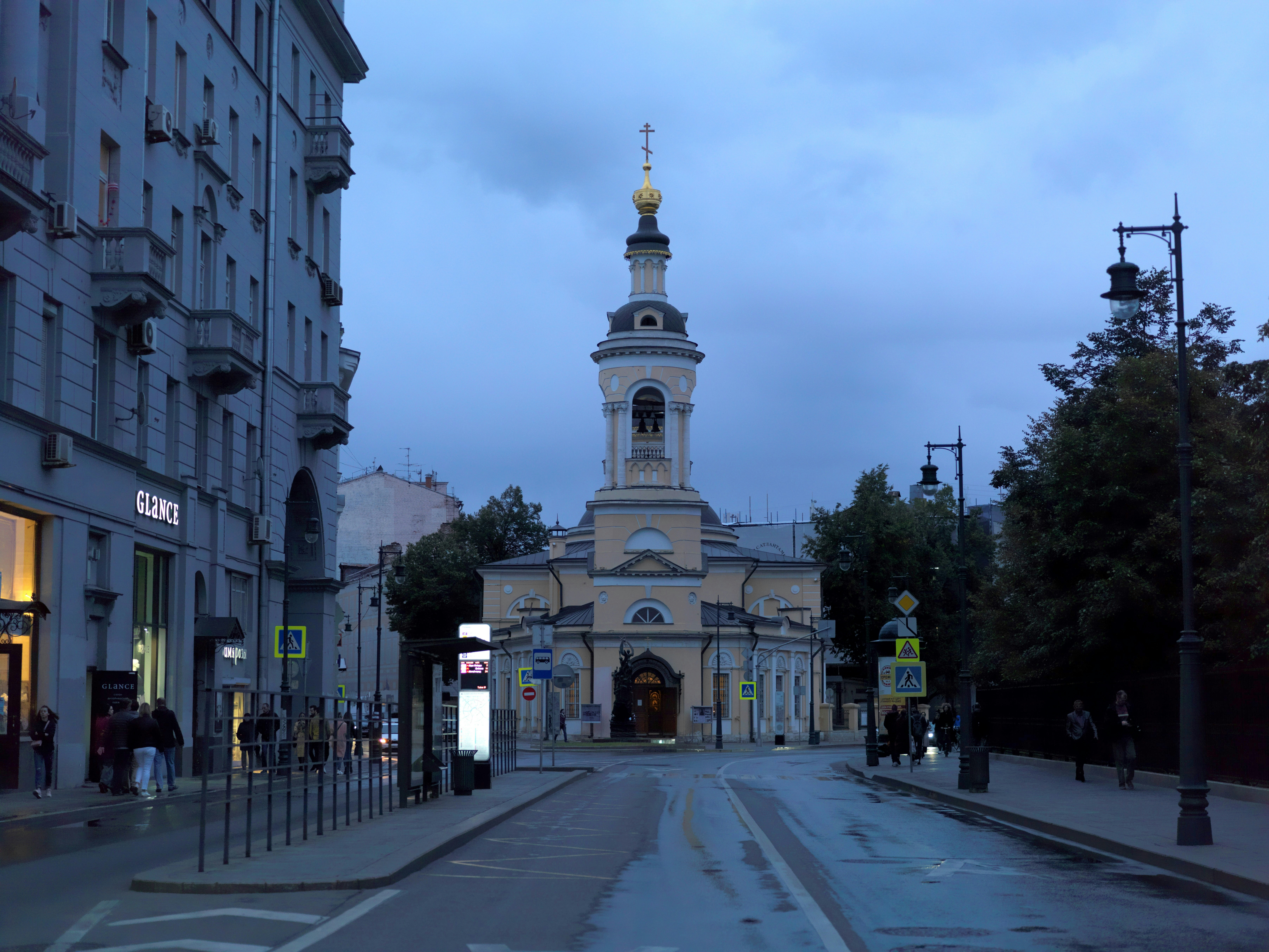 Evening street scene leading to a historic church under a dusky sky.
