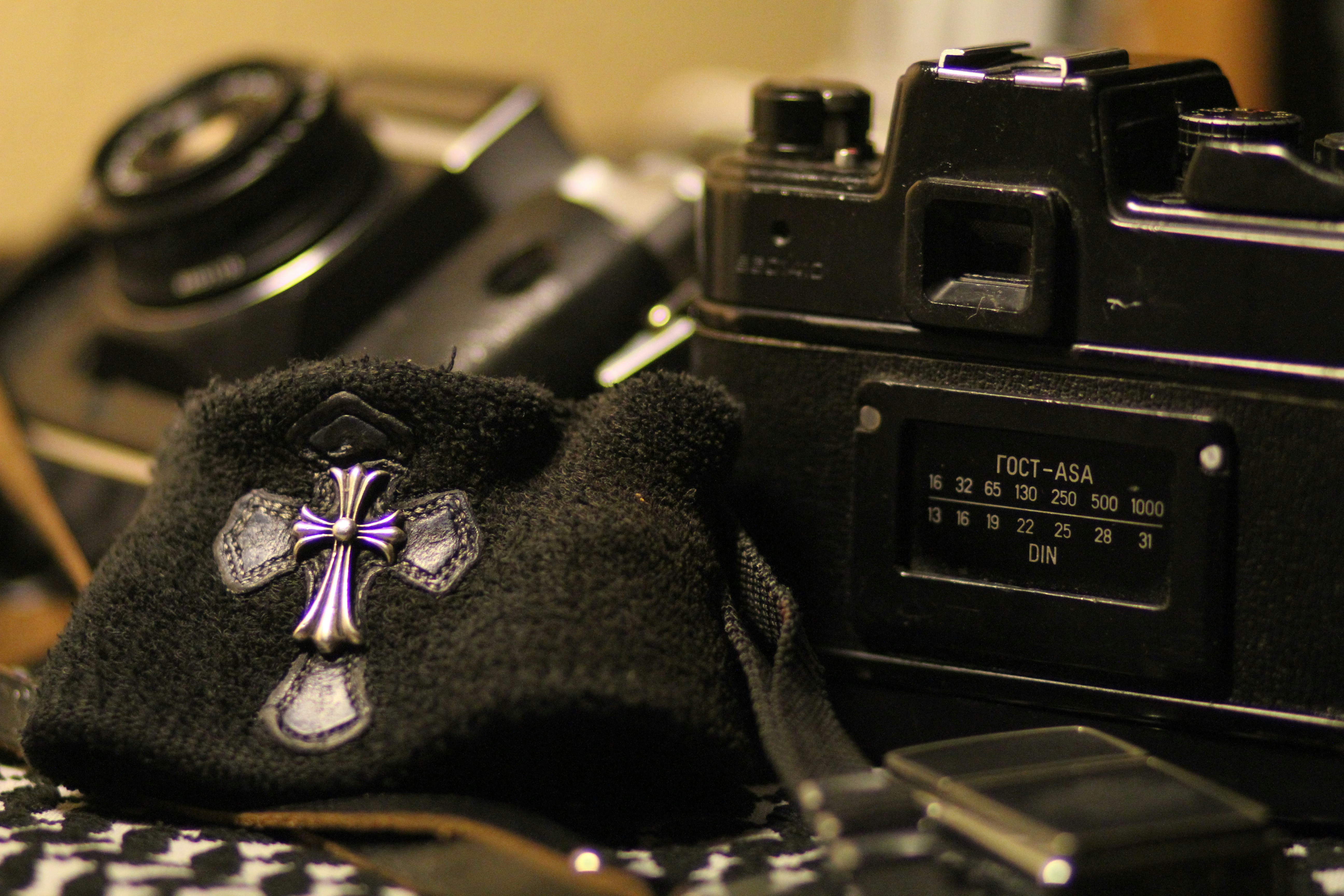 Vintage cameras and a textured cross pendant arranged on a patterned surface, evoking nostalgia for film photography.