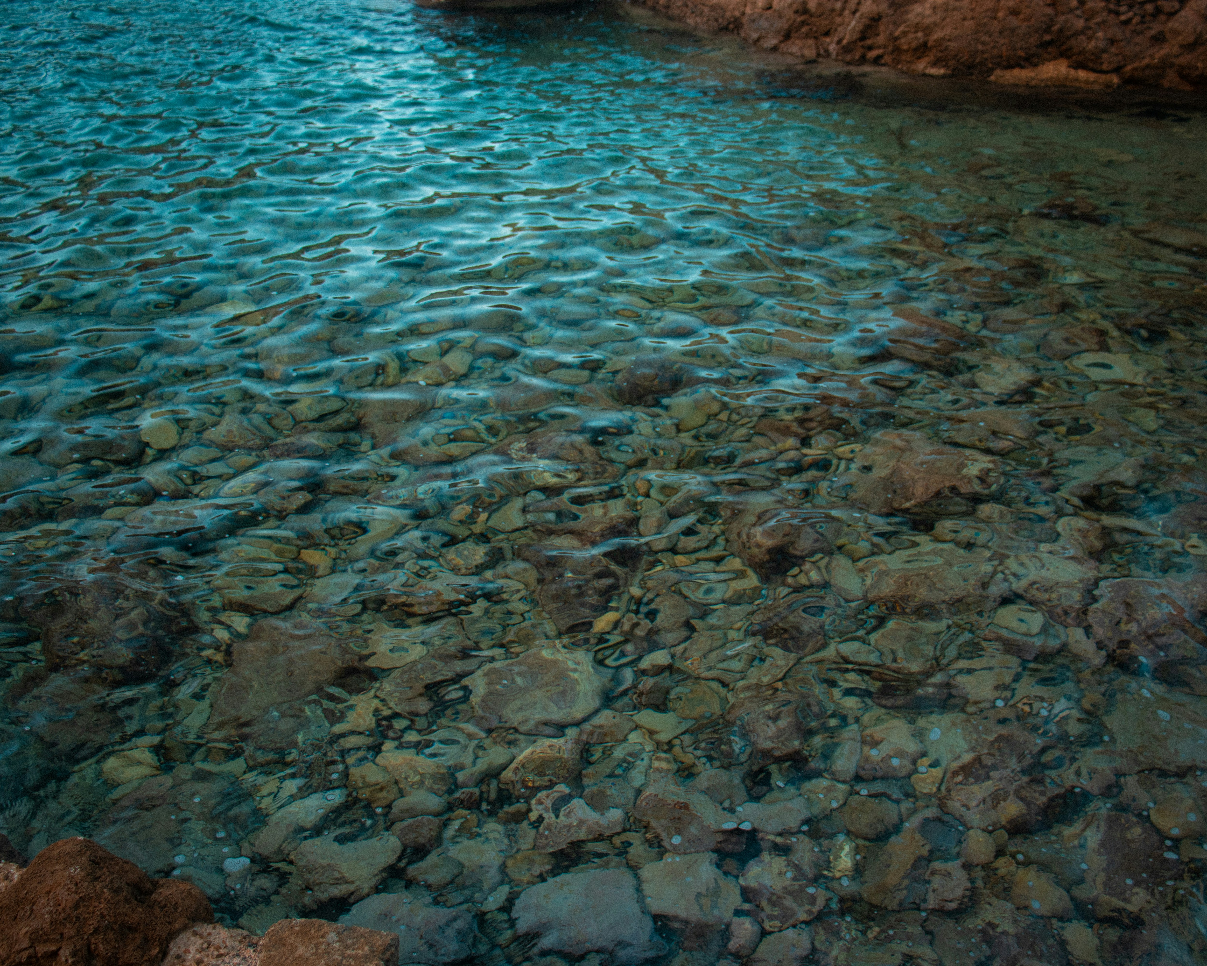Turquoise Depths: Pebble Mosaic Under Crystal Shoreline