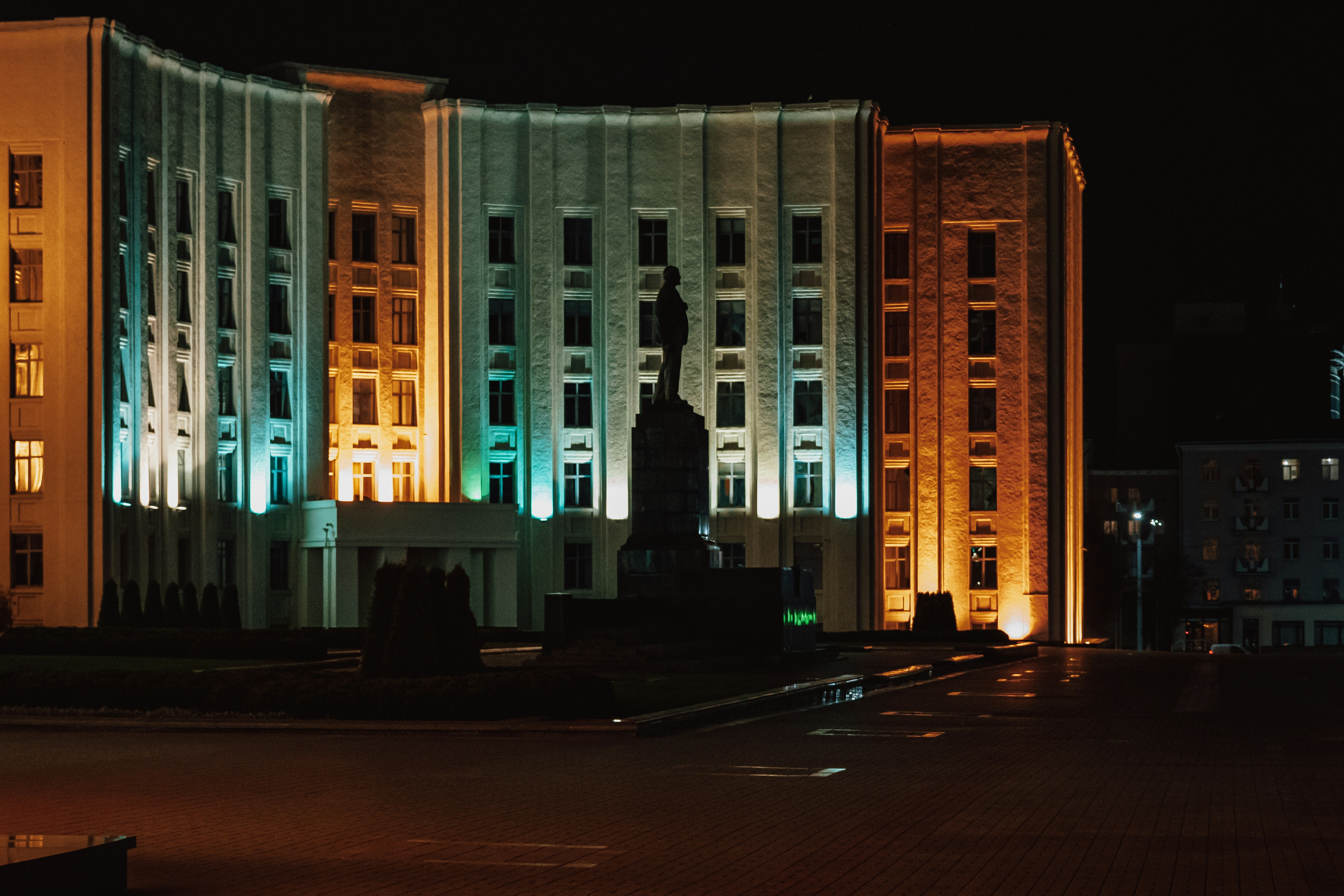 Historic building illuminated with vibrant lights, showcasing a central statue in a tranquil night setting.