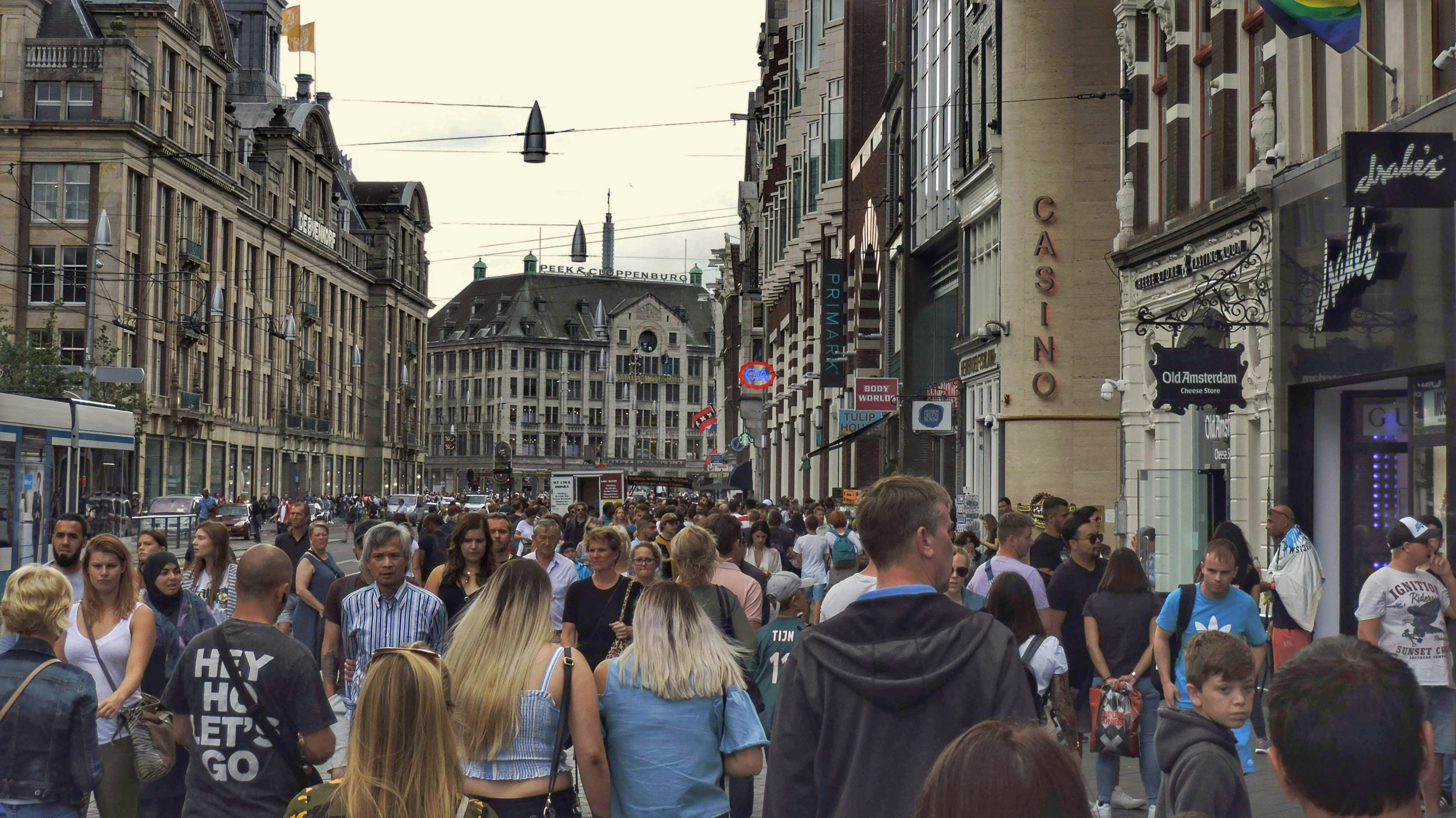 Bustling street scene filled with diverse crowds, showcasing shops and architecture in a lively urban environment.