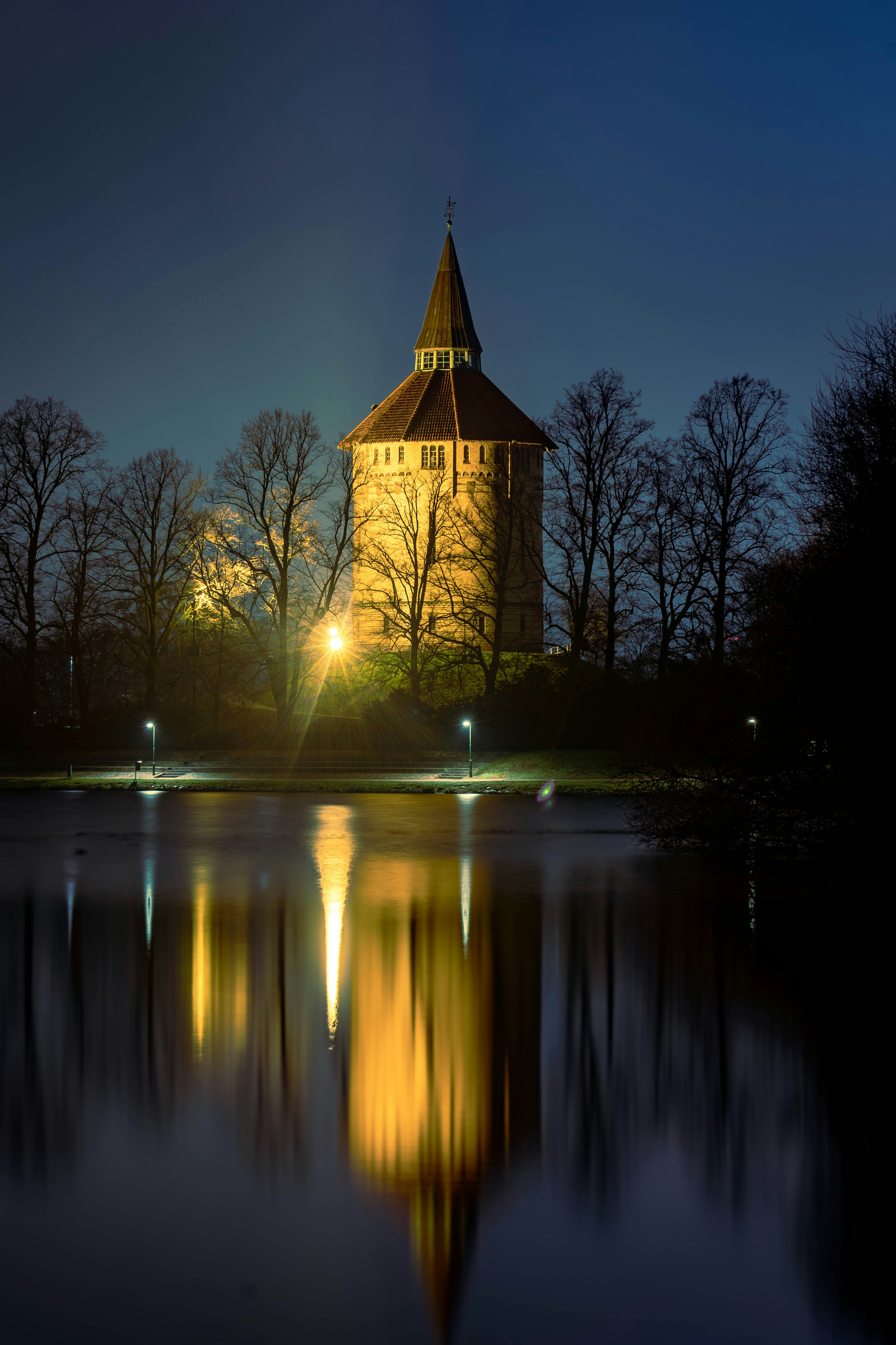 Amber Beacon by the Lake: Night Tower Casts Warm Light on Silent Water