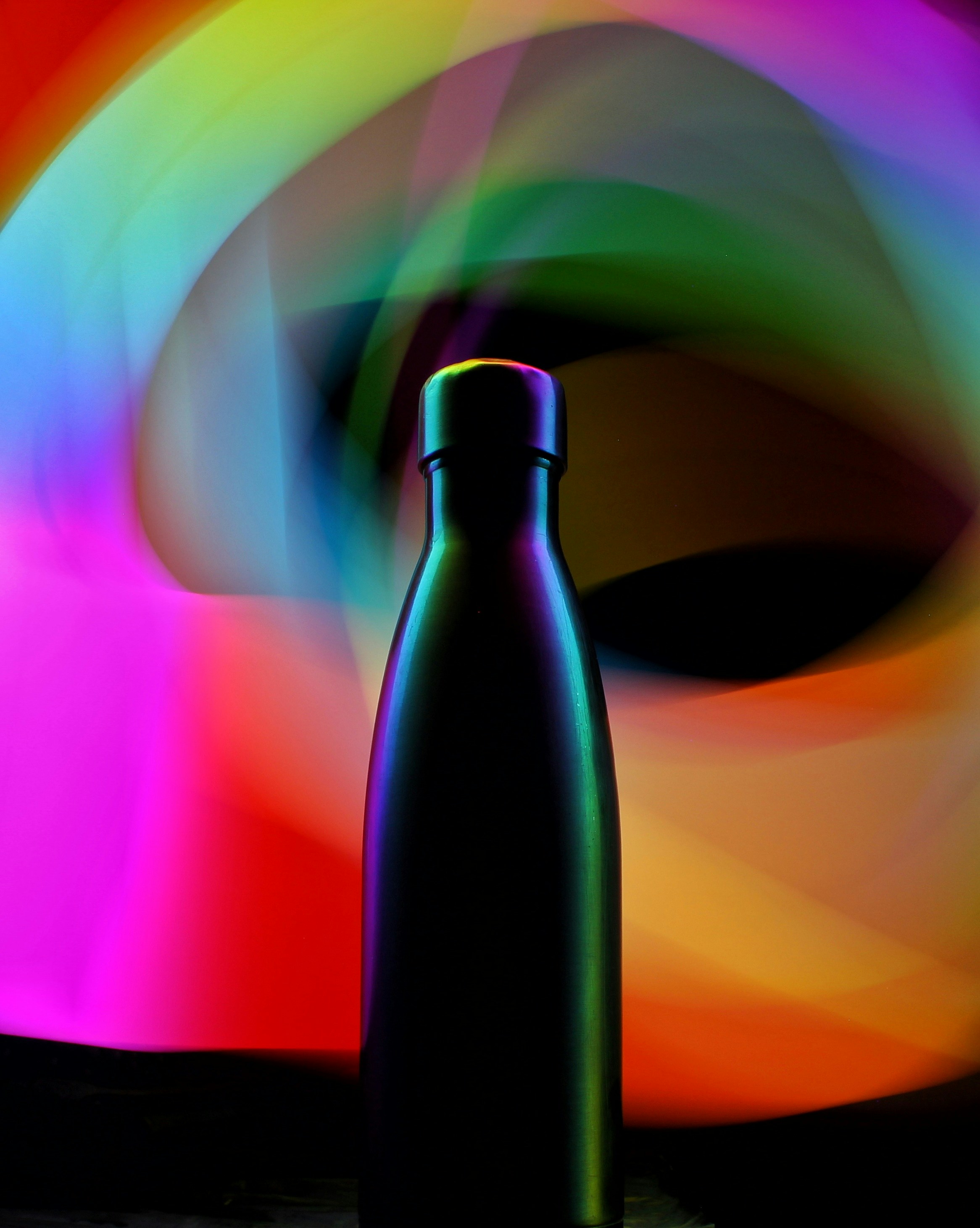 a black bottle with a multicolored background