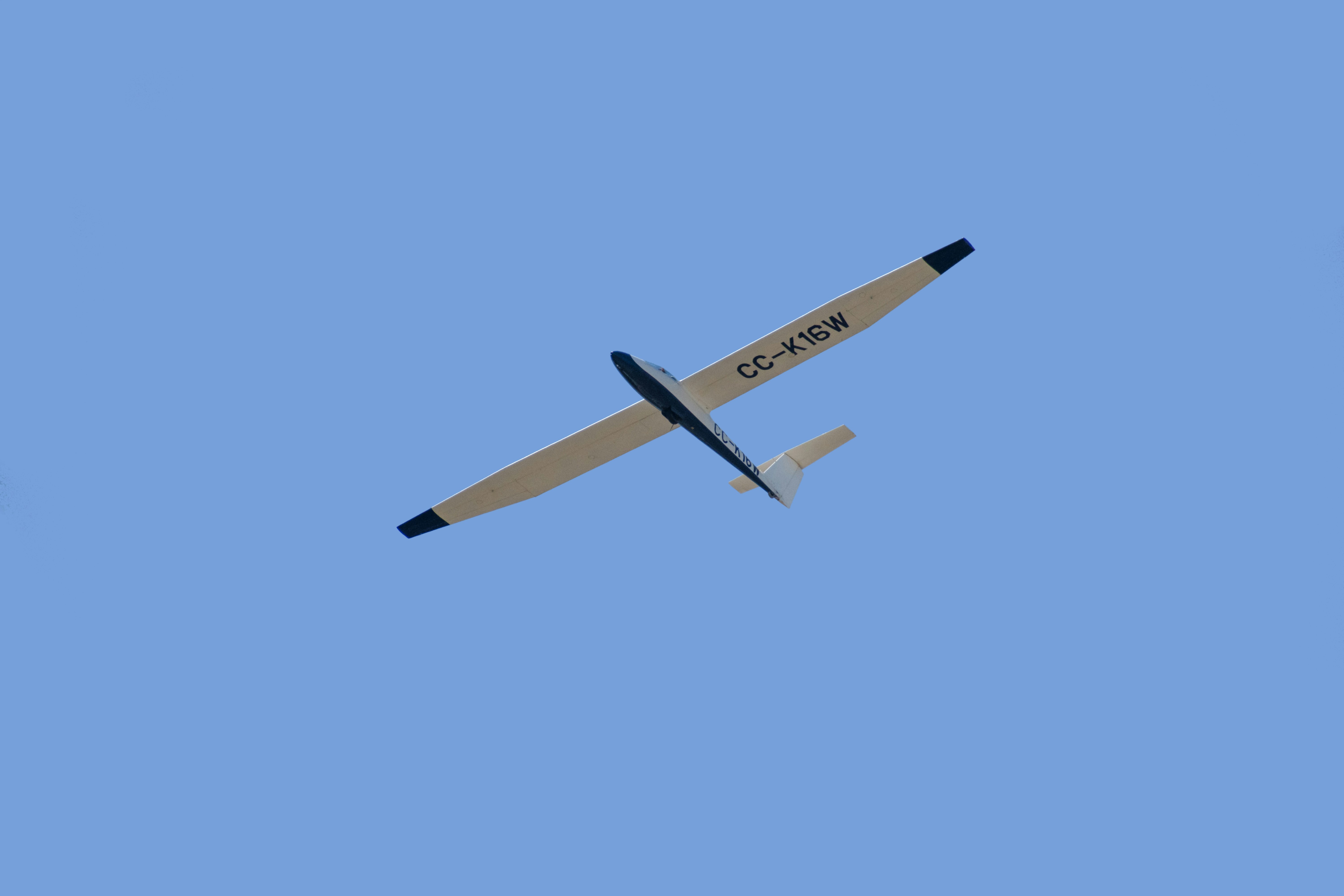 a small airplane flying through a blue sky