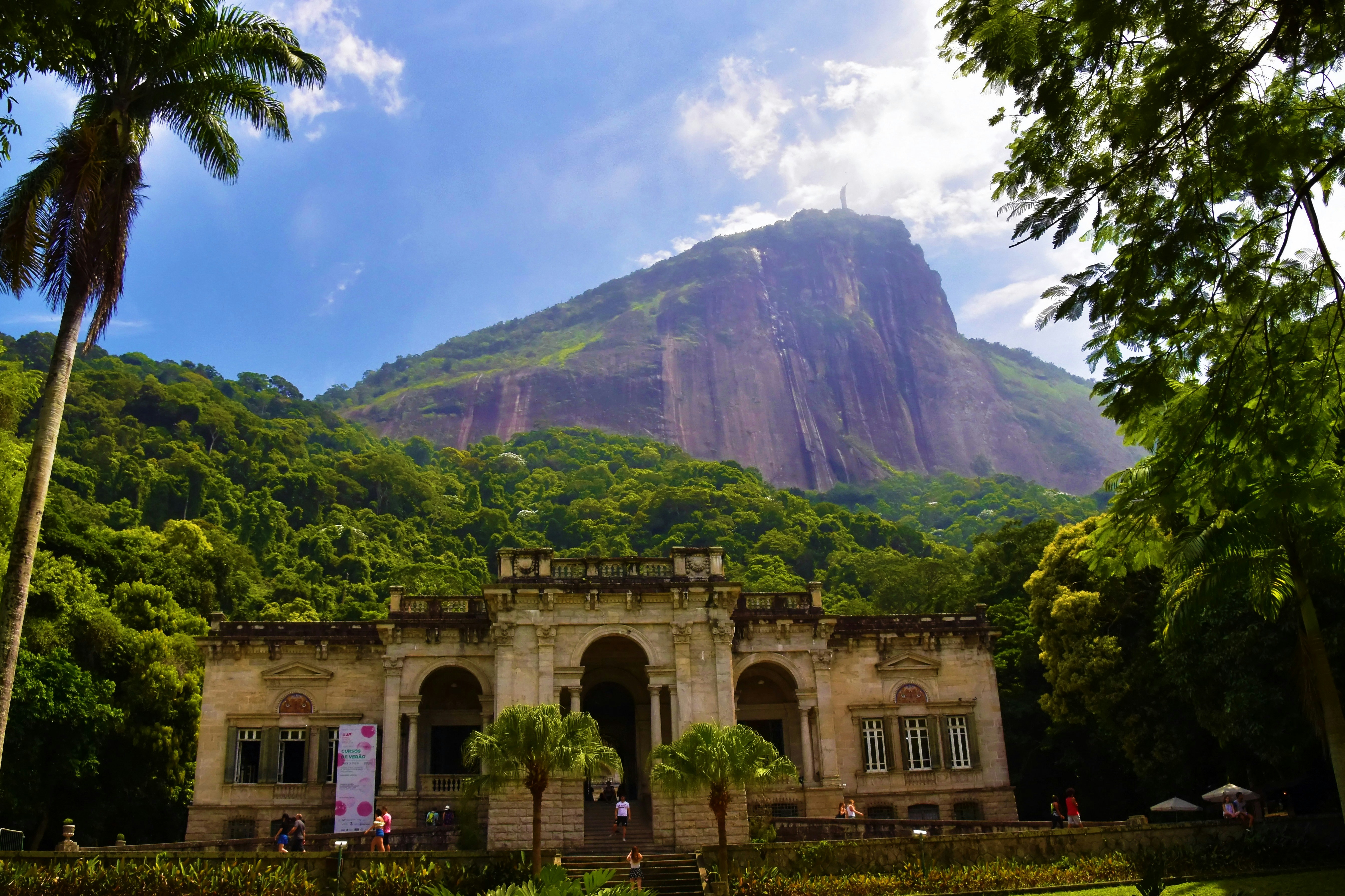 Stone Gateway Framed by Palms Against a Verdant Peak