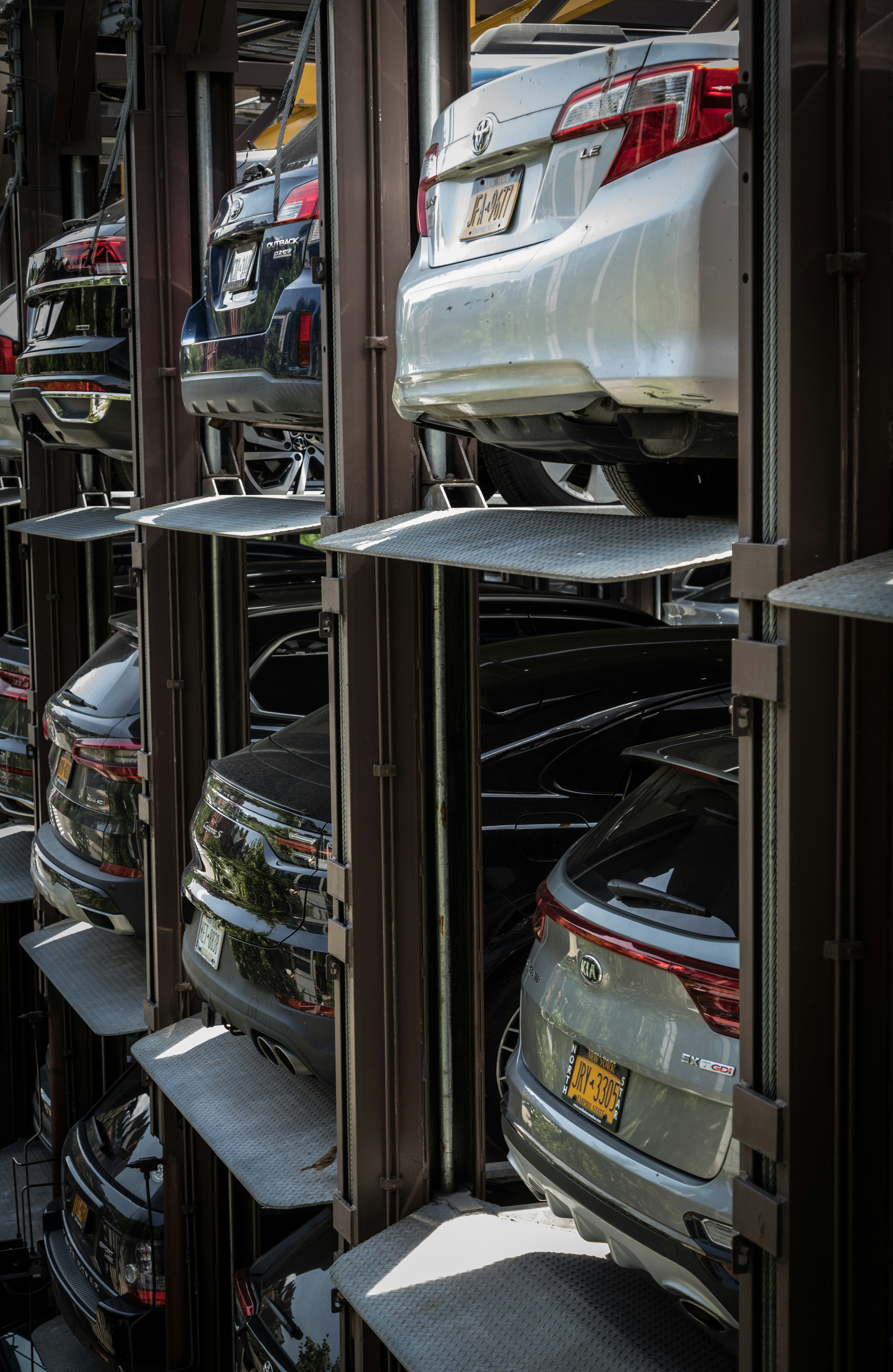 Vertical Stack of Sedans: A Quiet Chrome Opera in a Metal Lift