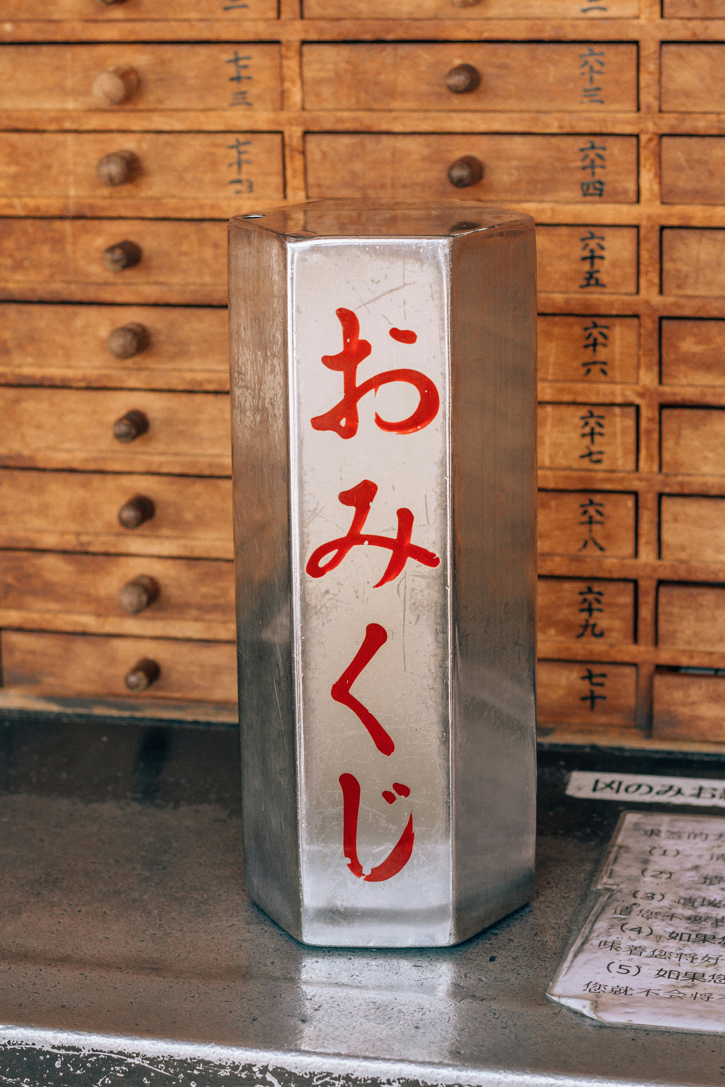 Red Omikuji Plaque Rising Against a Wall of Shrine Drawers