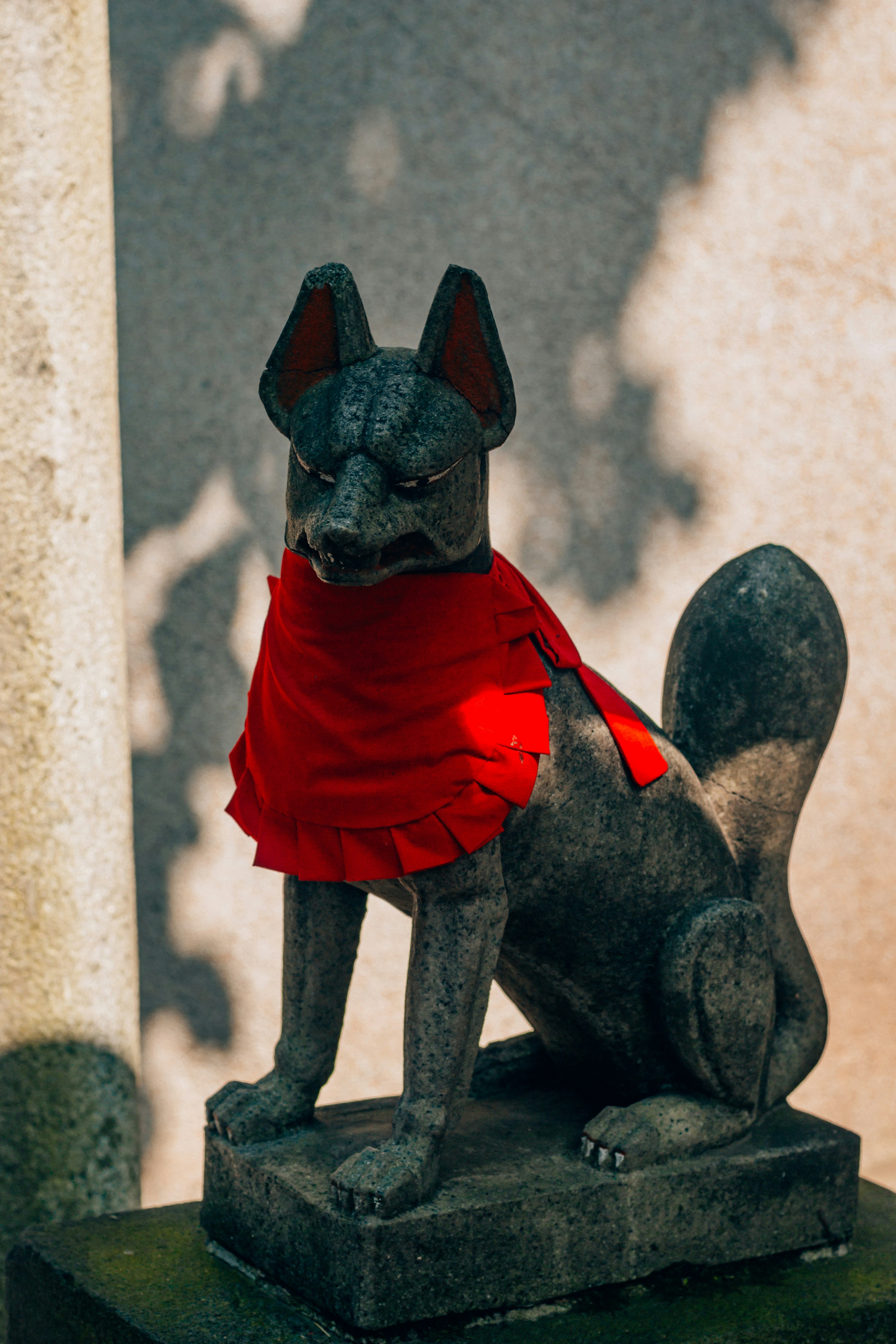 Red-scarfed guardian: a stone fox statue watches over the courtyard