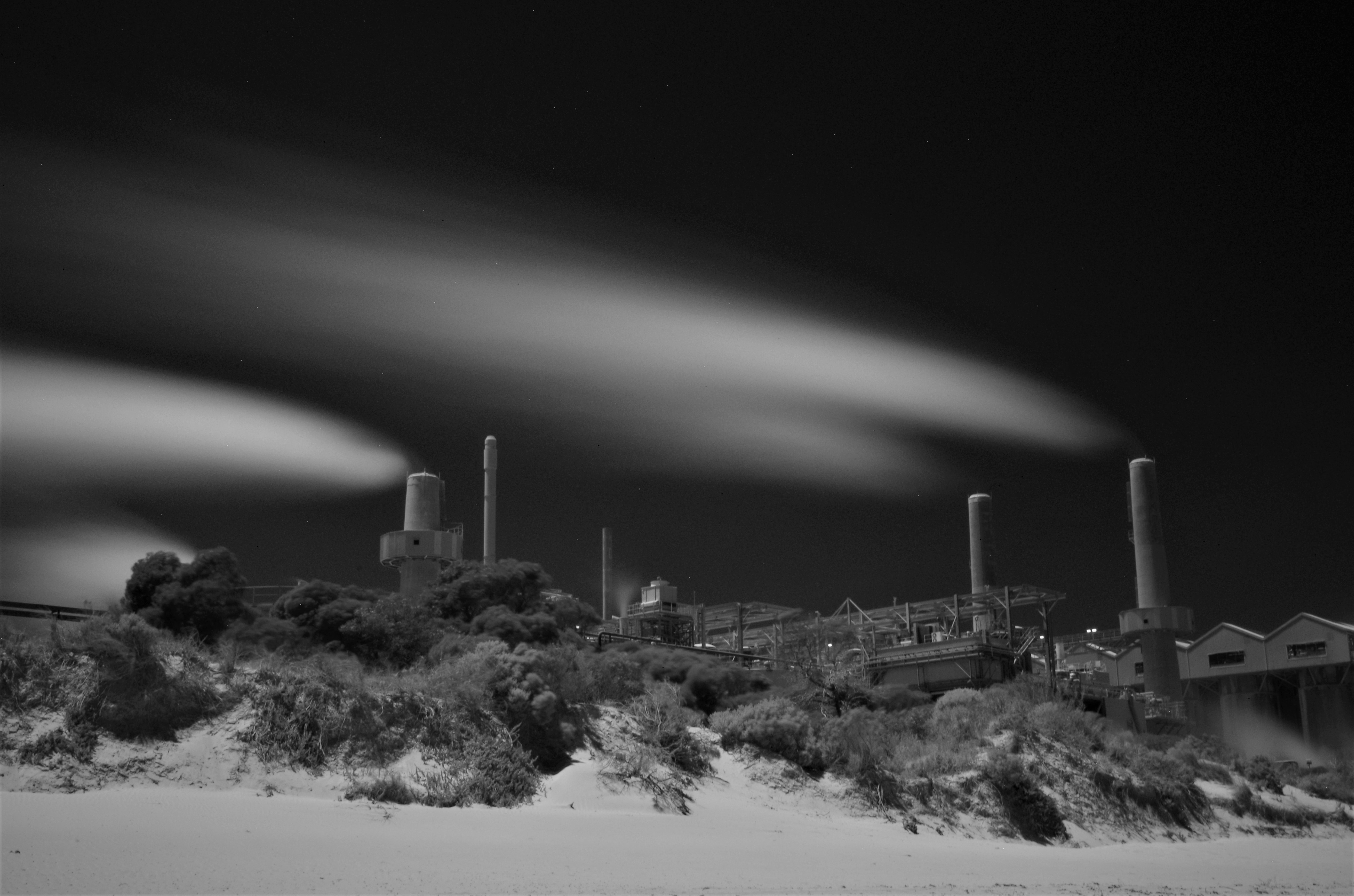 Night Shifts Beneath a Starry Sky: Long-Exposure Monochrome of an Industrial Spine
