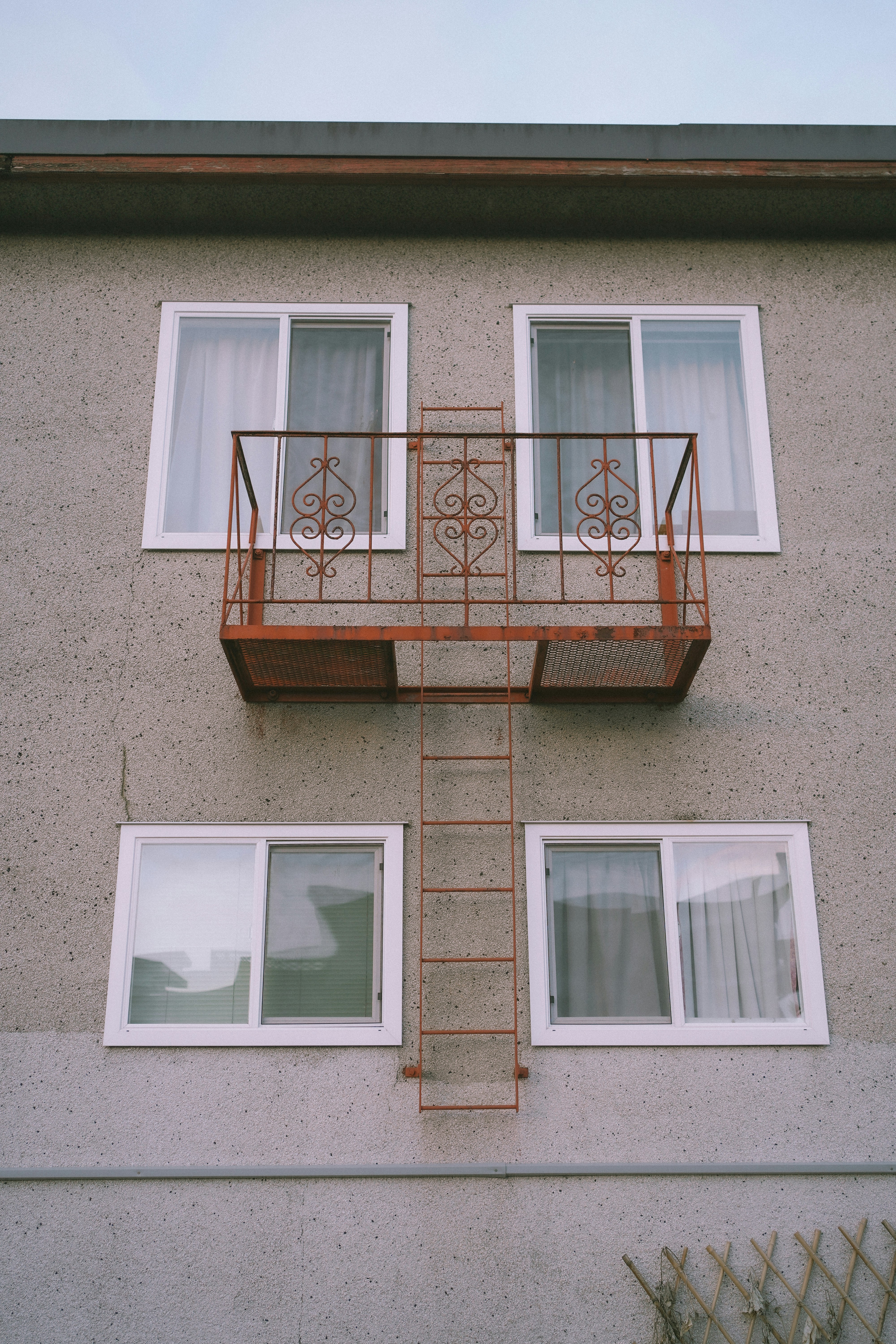 Ironwork Between Windows: A Weathered Balcony on a Quiet Facade