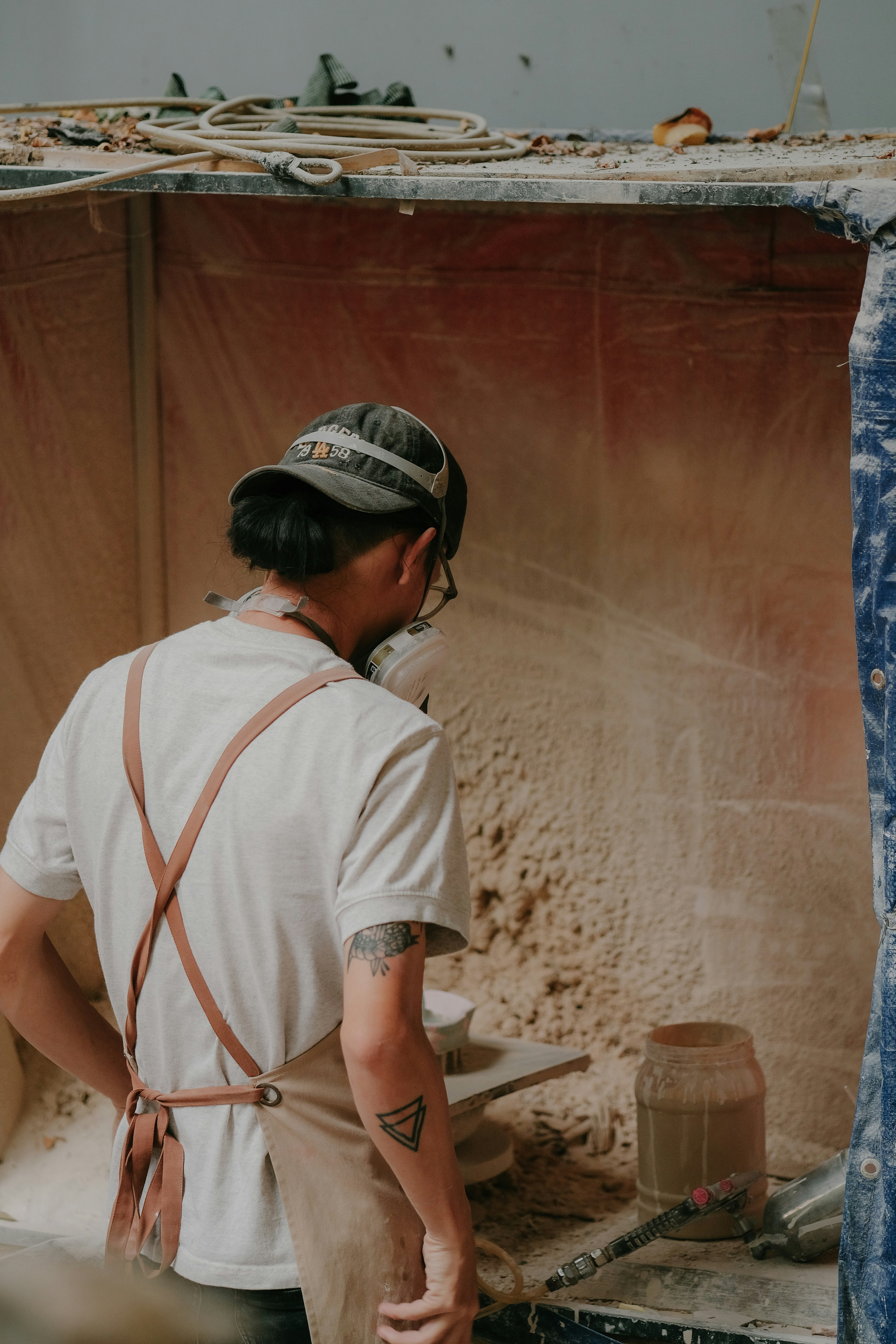 a man in a hat and apron working on a piece of pottery
